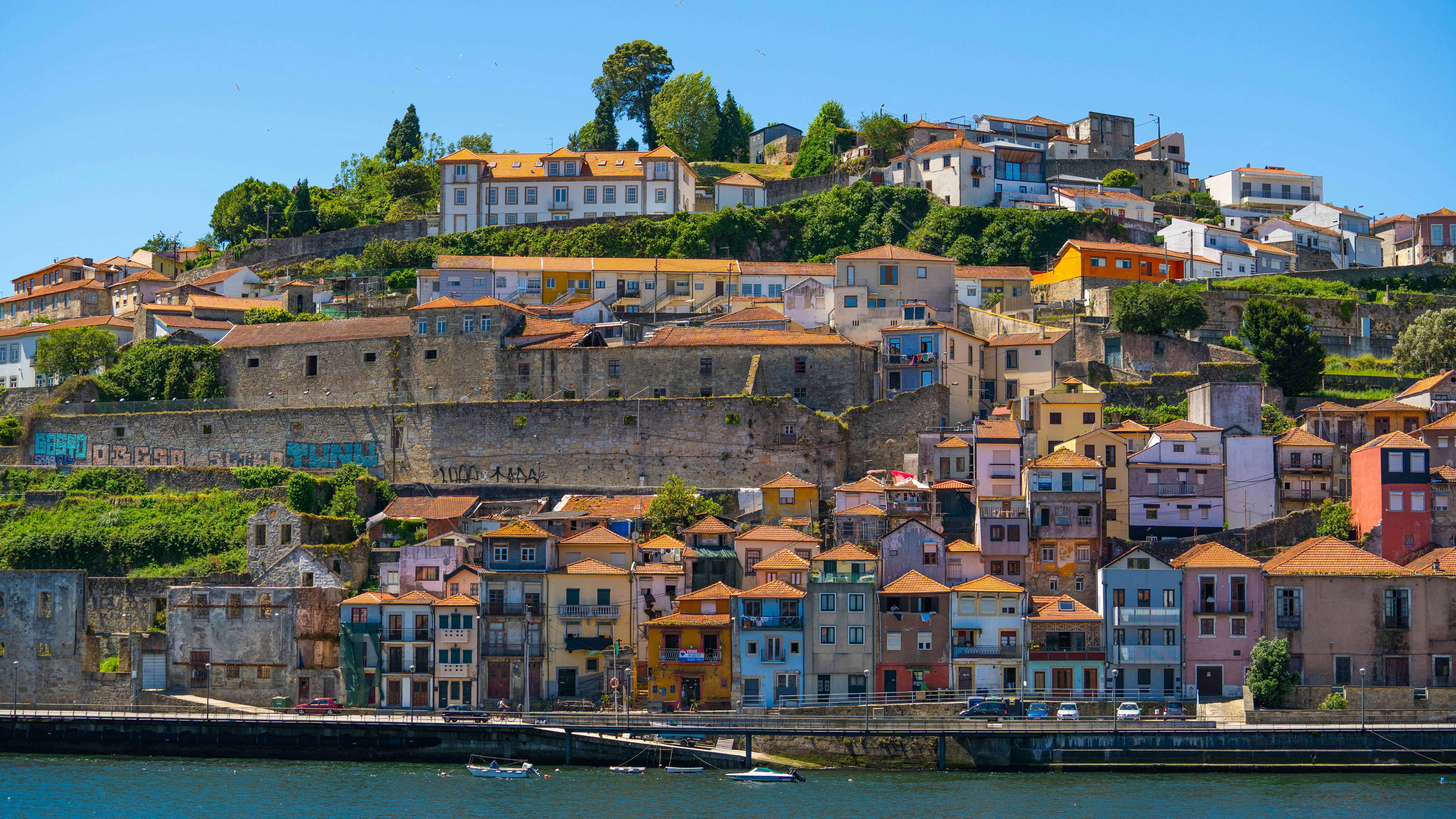 Vibrant, multicolored buildings cascade down a lush hillside under a clear blue sky.