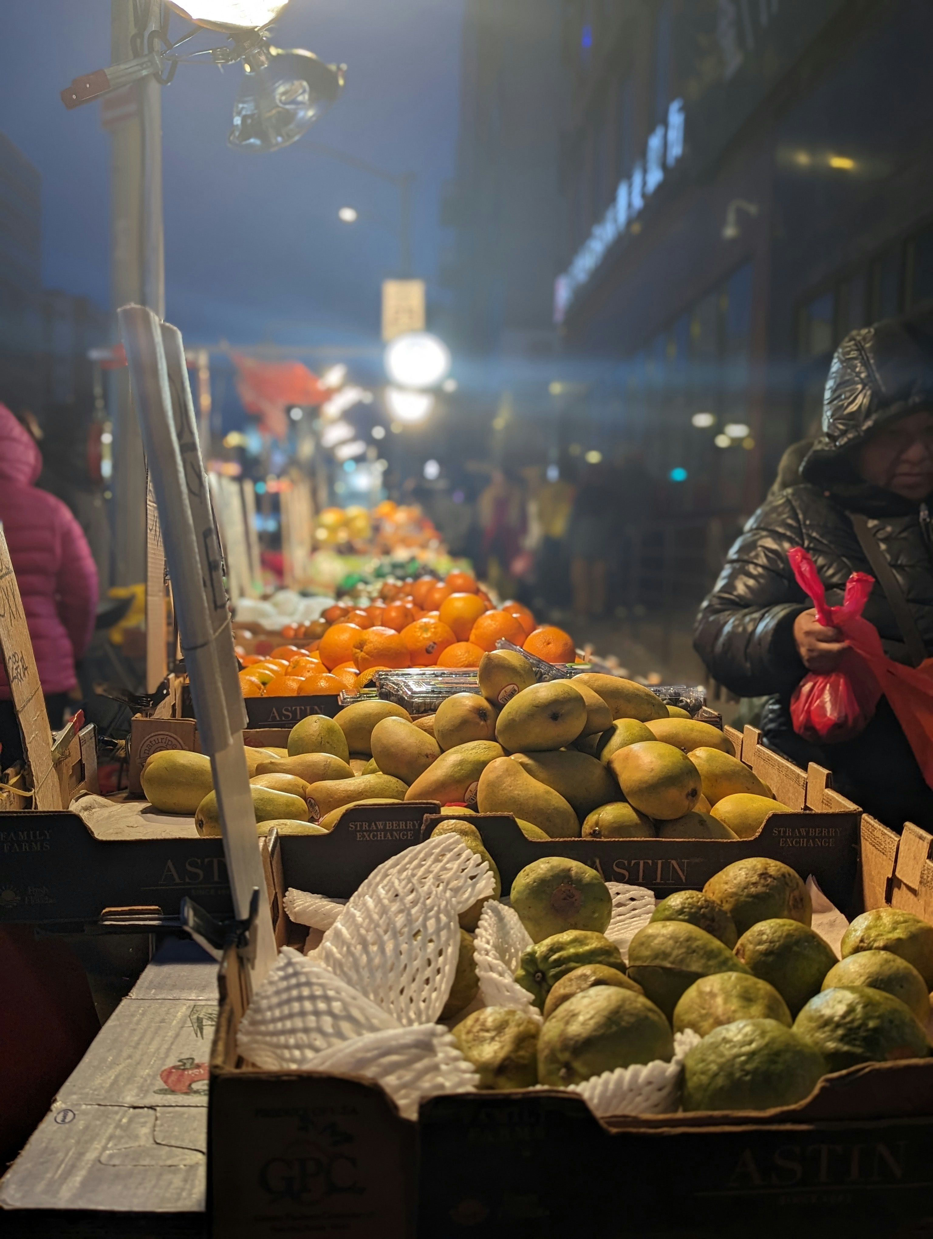Under Neon Glow: Fresh Mangoes and Oranges at a City Night Market