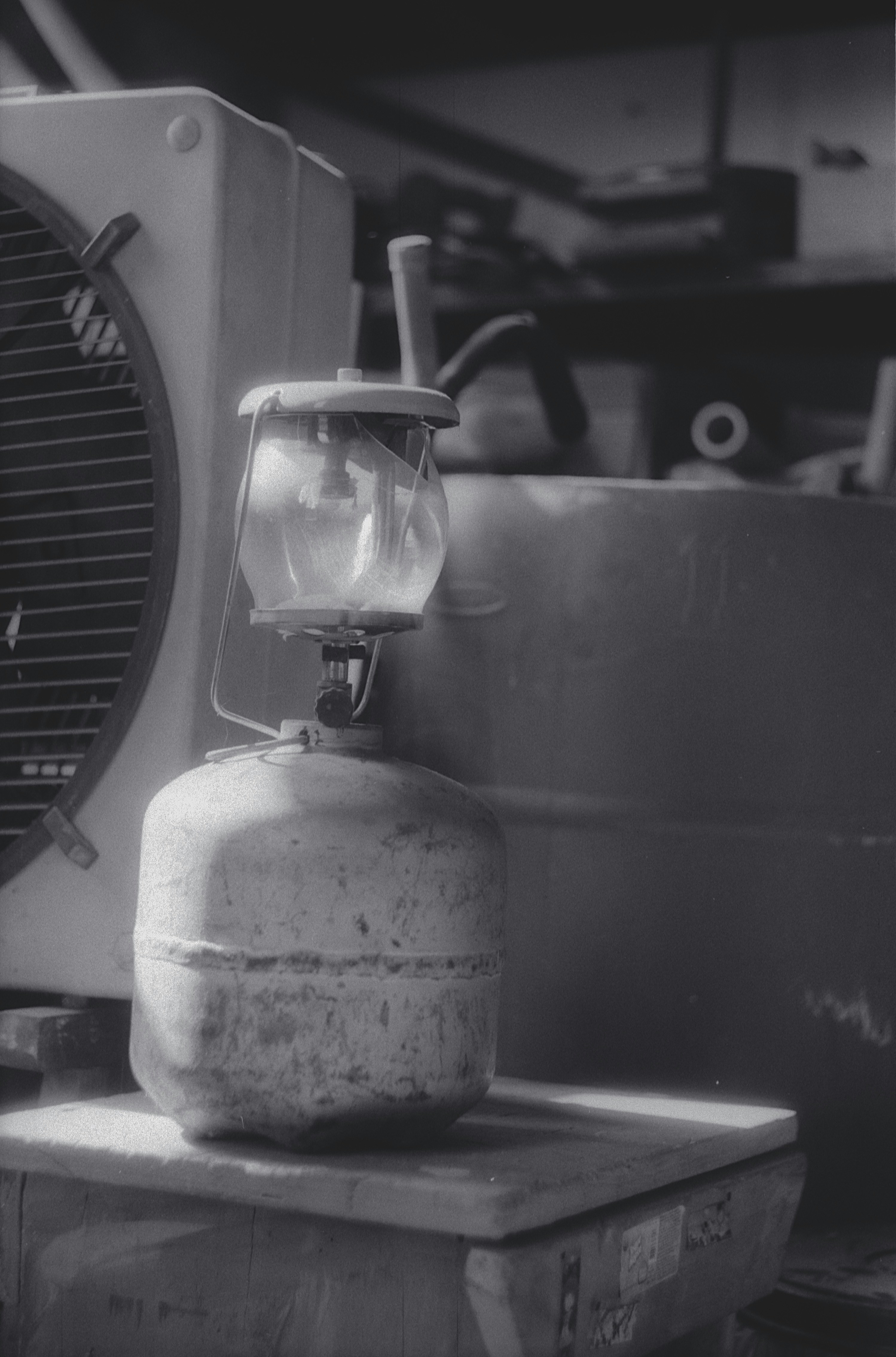 Dim Workshop Lantern: A Weathered Propane Lamp on a Rusted Cylinder