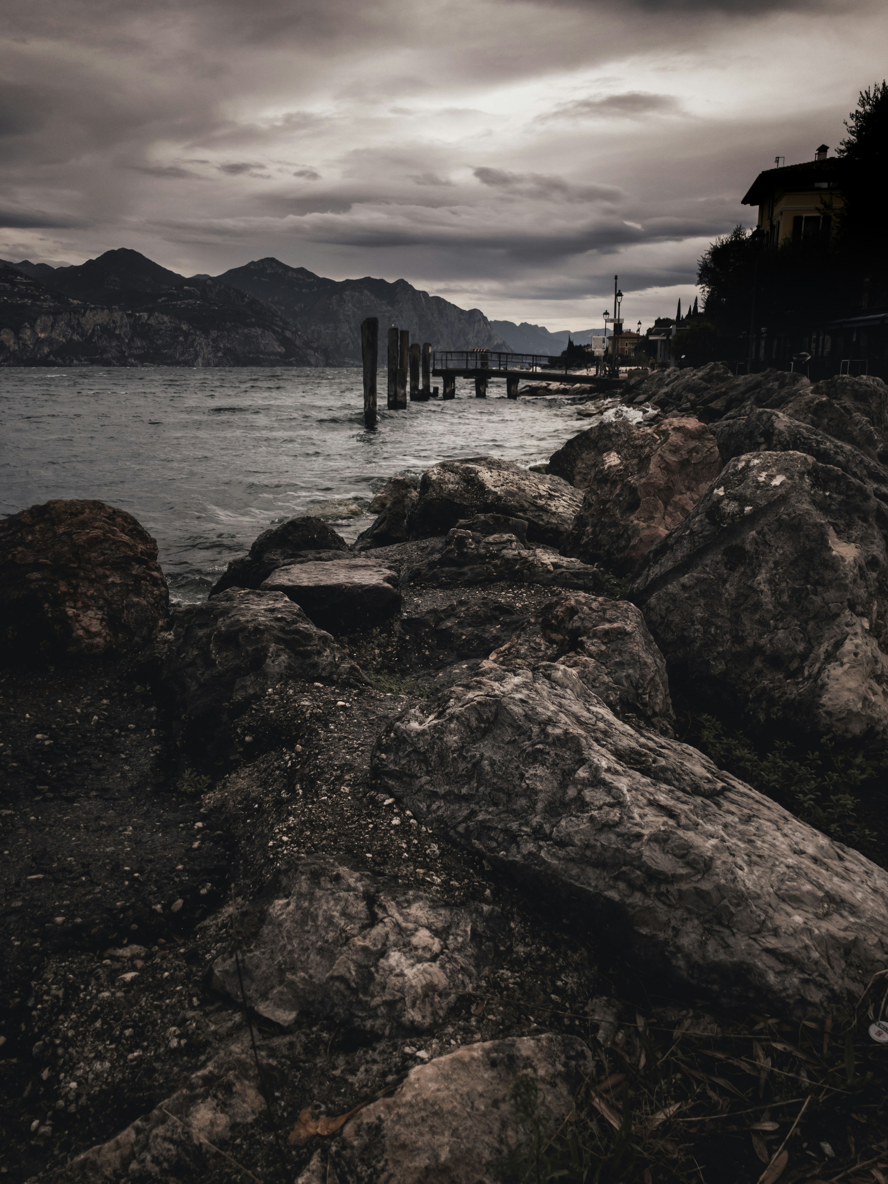 Weathered Jetty Through Jagged Rocks Toward a Cloudy Lake Horizon