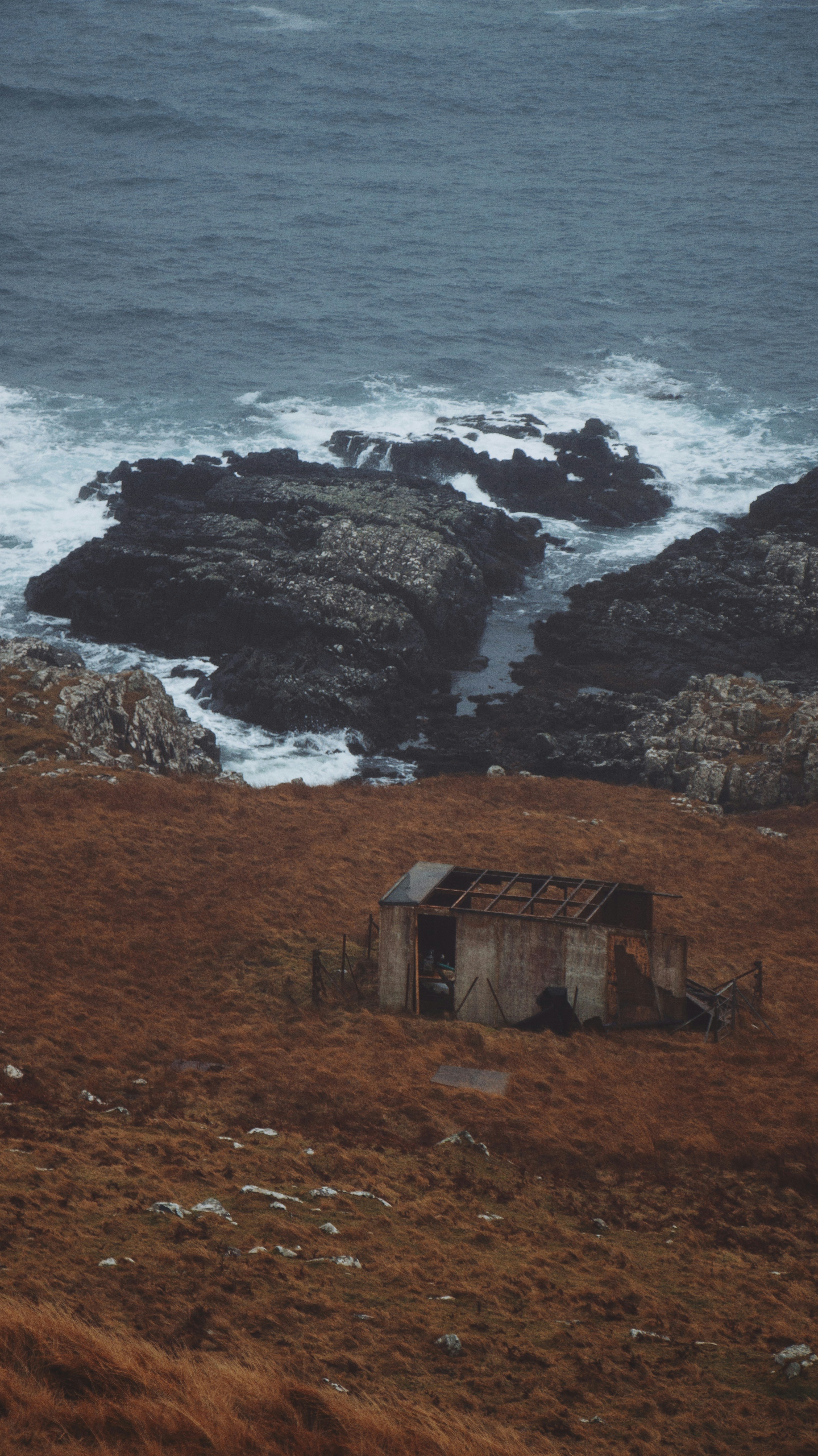 A small shack sitting on top of a grass covered field photo – Free Grey ...