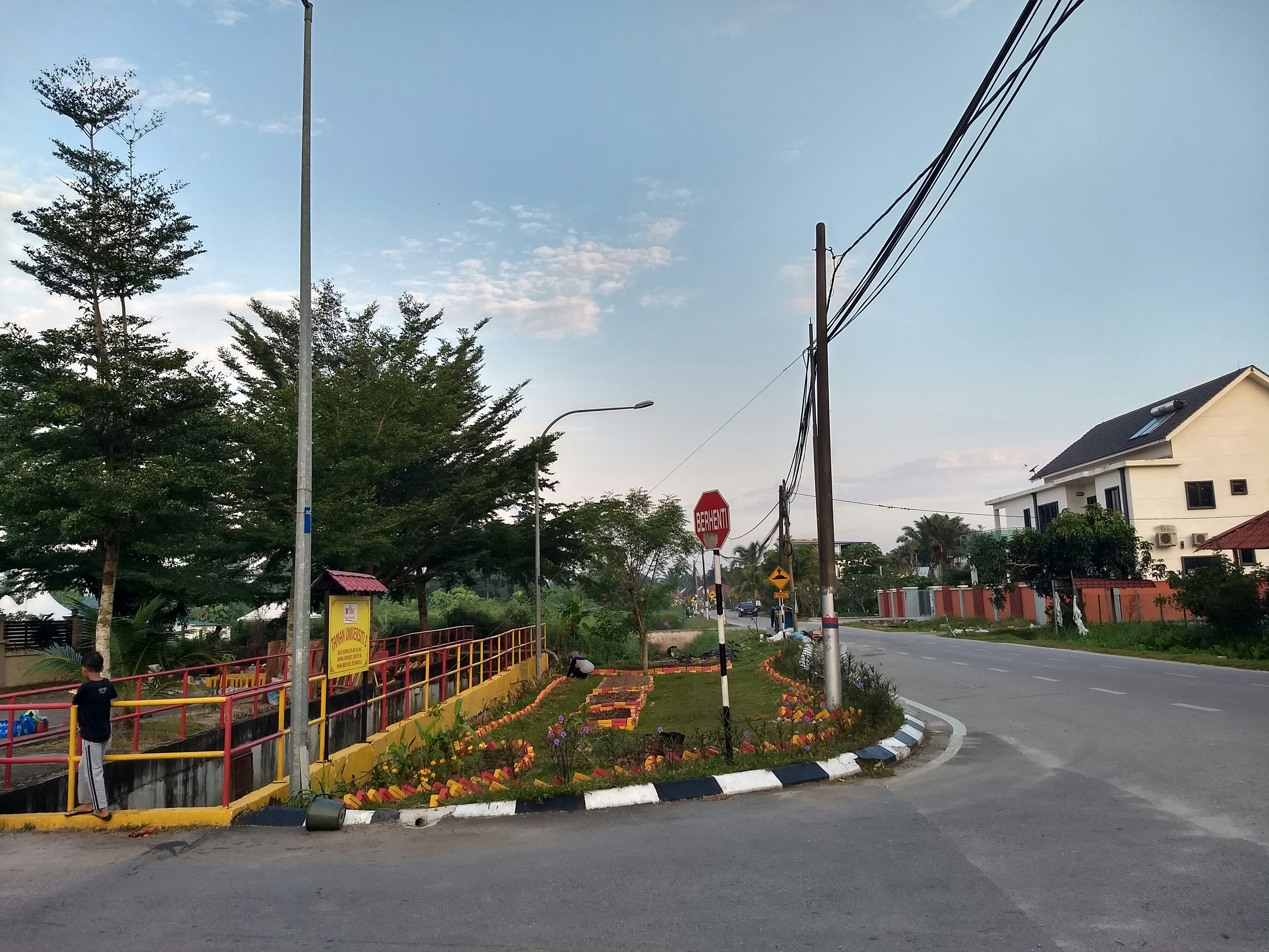 a street with a fence and flowers on the side of the road