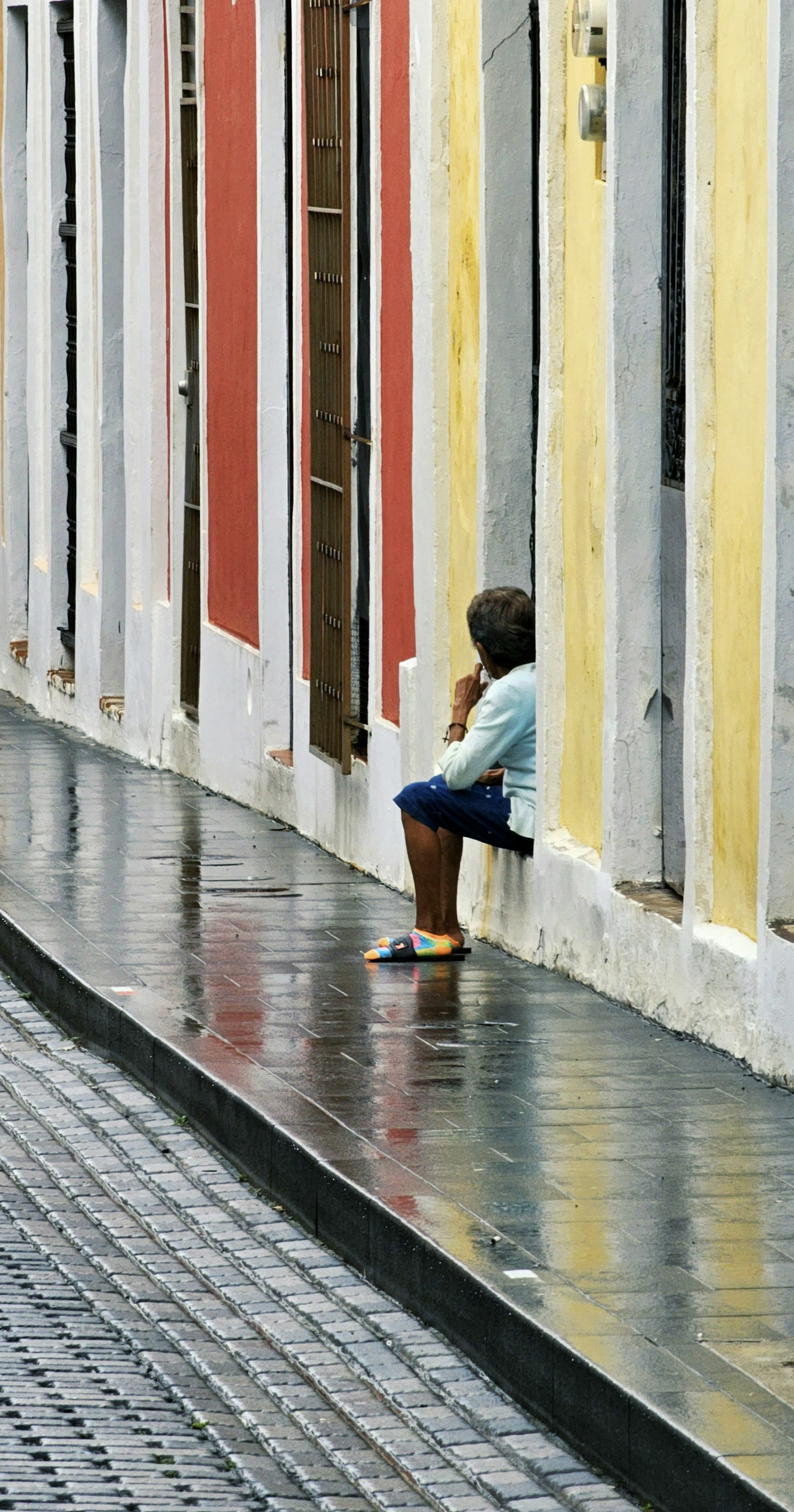 A person sitting on the ground in front of a building photo – Free City ...