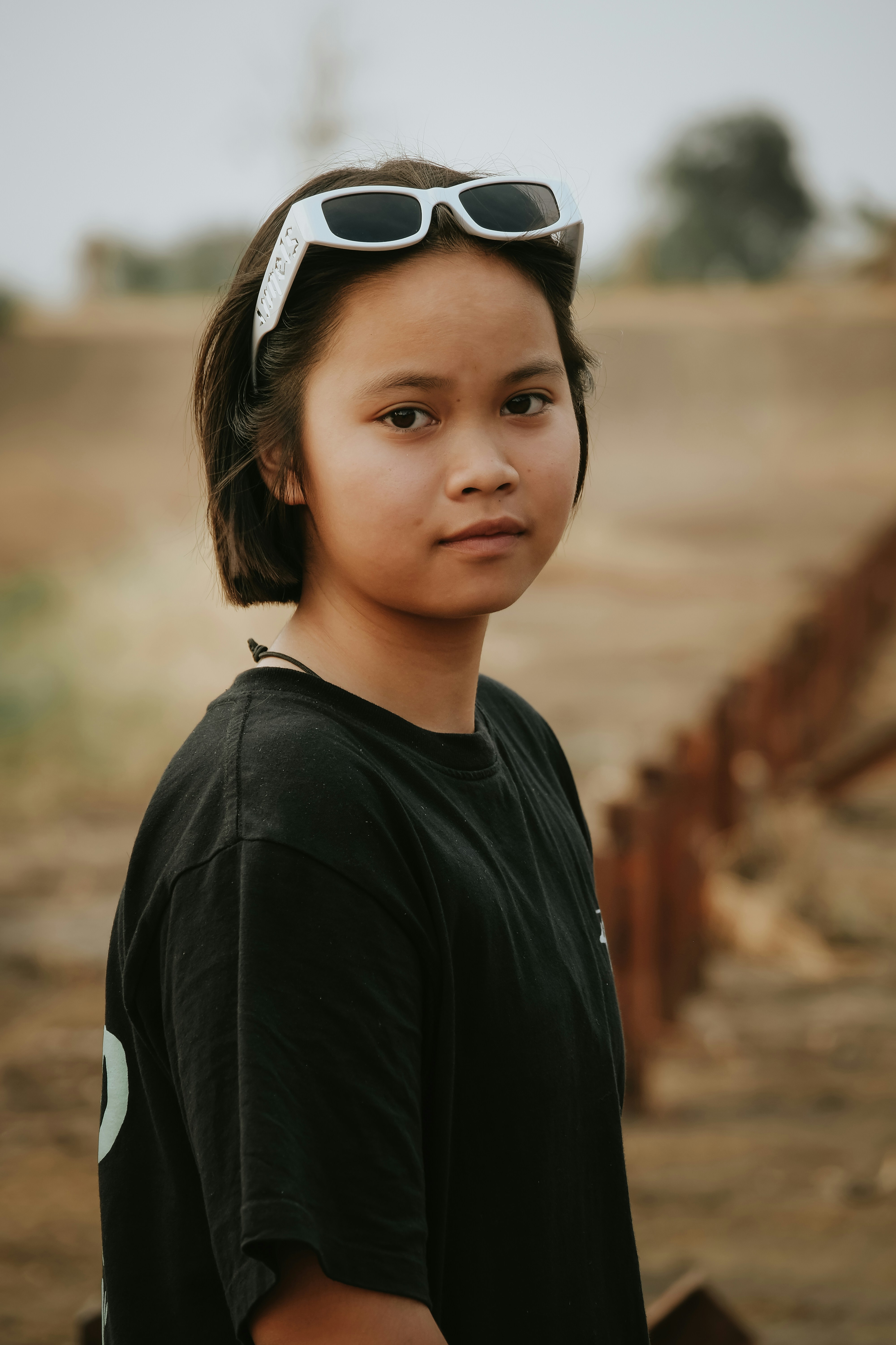 Quiet Confidence: Portrait of a Girl with Sunglasses on a Desaturated Trail
