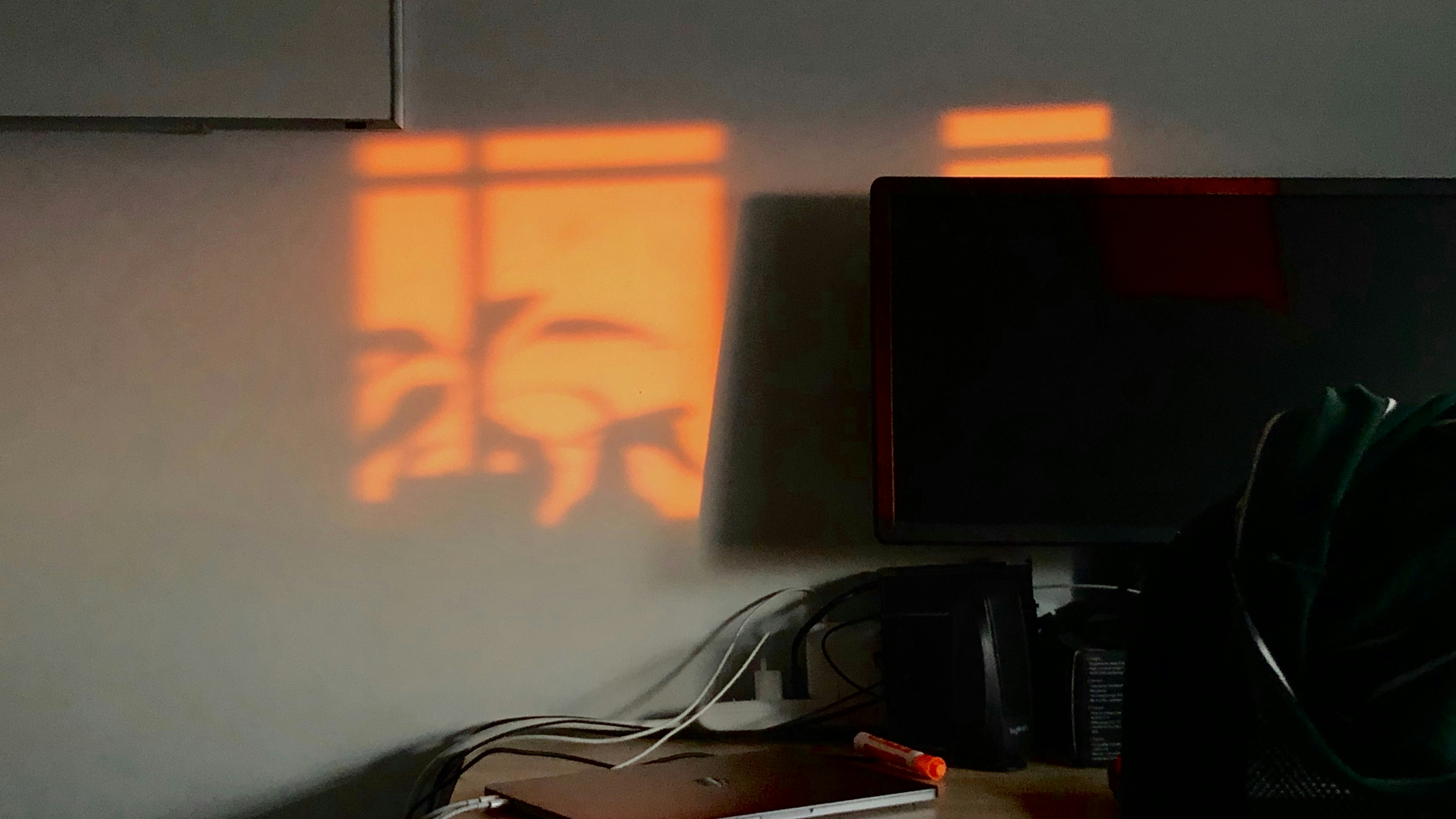 Sunset Grid on a Desk: Orange Light Through Slats Illuminates Cables and Monitor