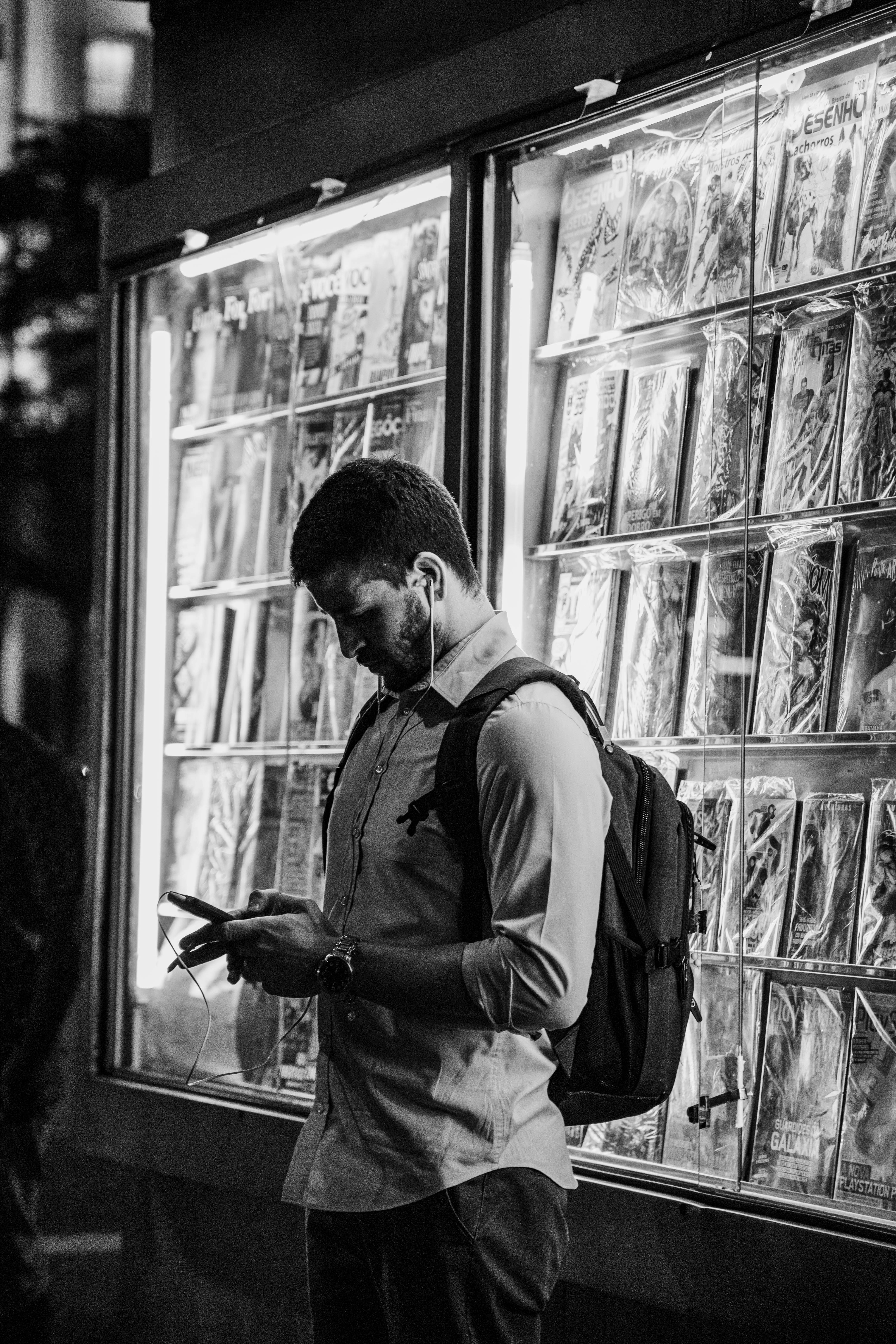 a man standing in front of a store looking at his cell phone