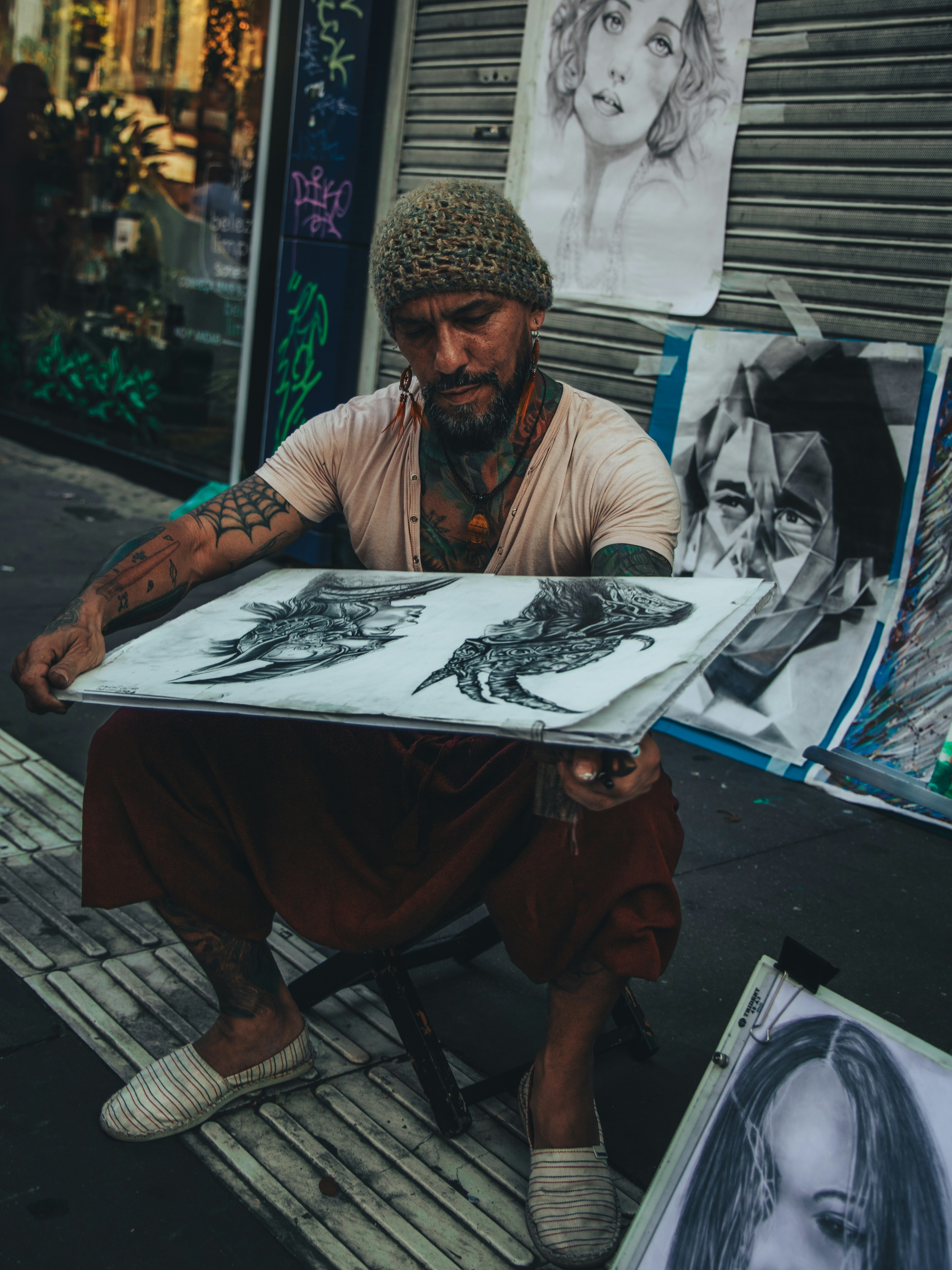 a man sitting on a sidewalk holding a piece of artDarwin Boaventura