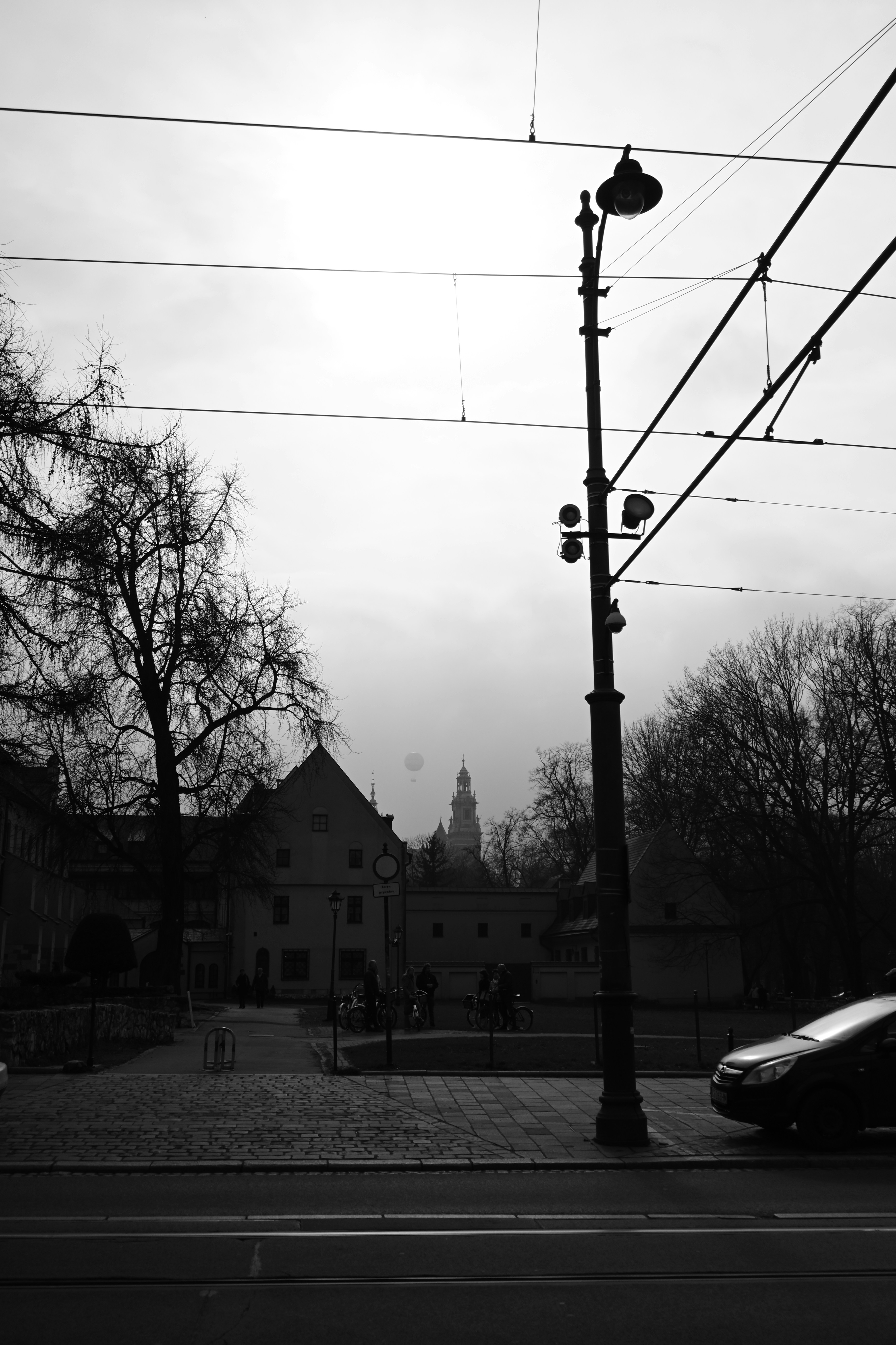 Lamppost Geometry: A Monochrome Street Framed by Wires and a Distant Church Tower