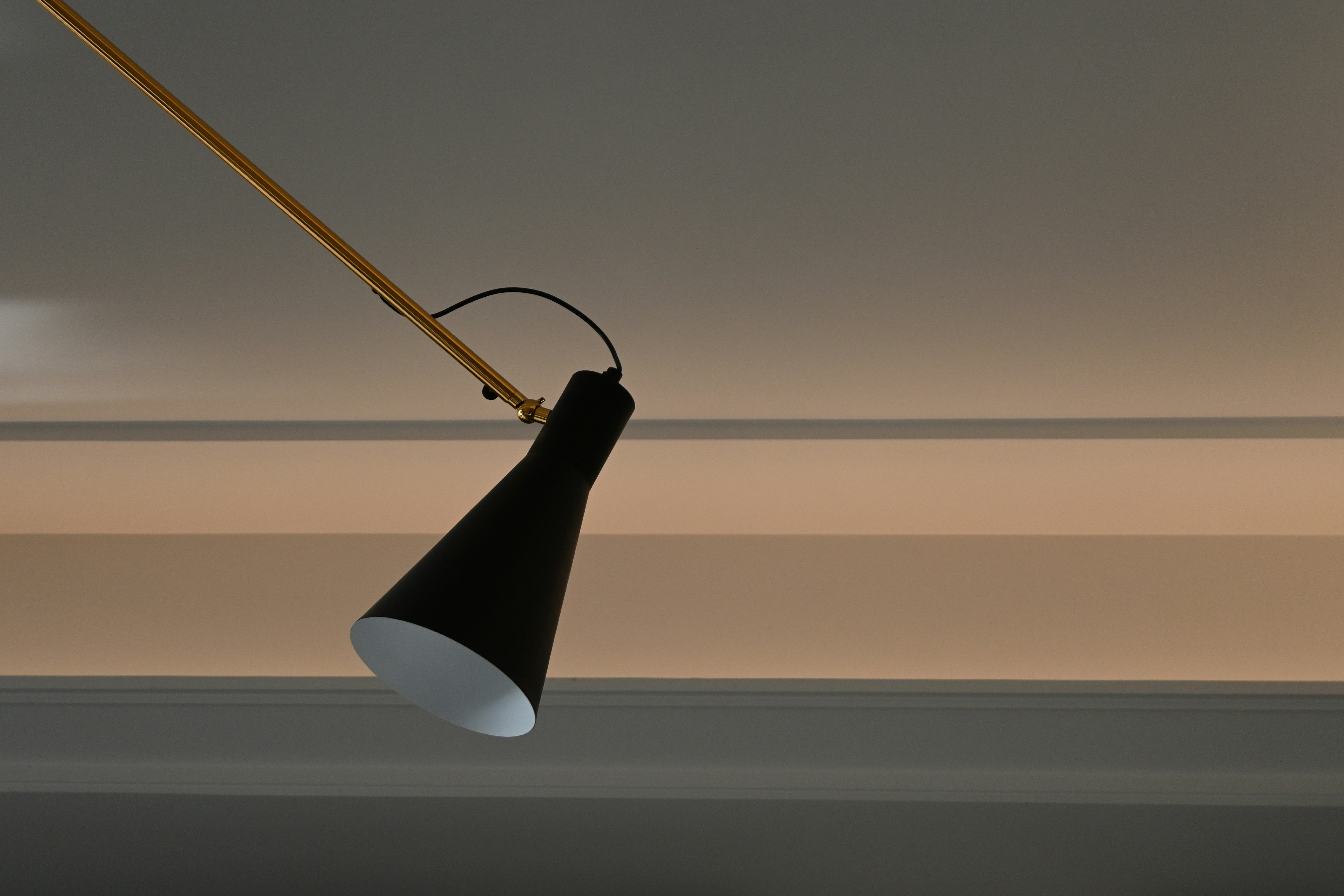 Mid-Century Brass Arm Illuminates a Quiet Gradient Ceiling