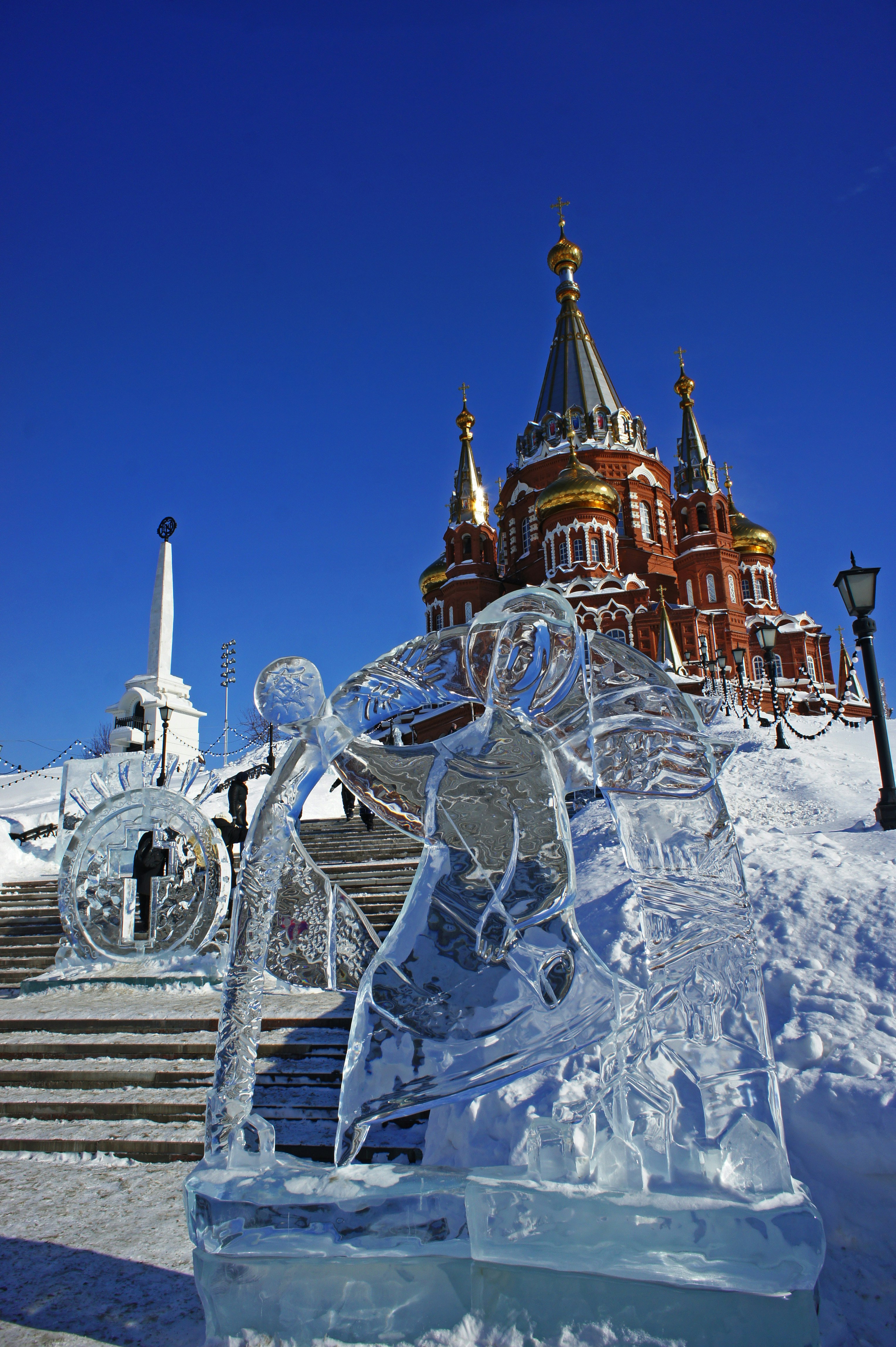Ice-carved Figures on Snowy Steps Before a Golden-Domed Cathedral