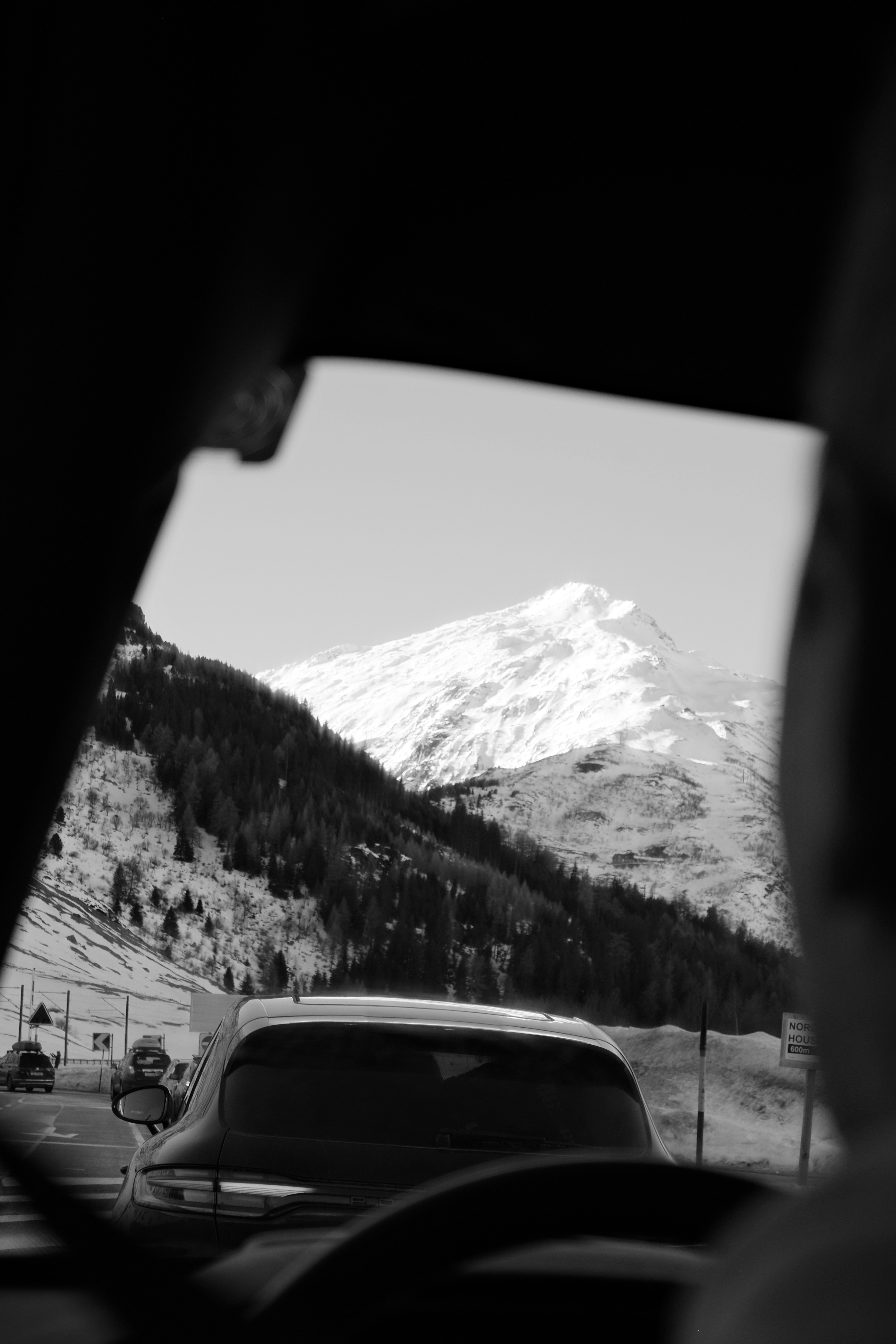 Snow-Capped Summit Framed by a Car Window in a Mountain Pass