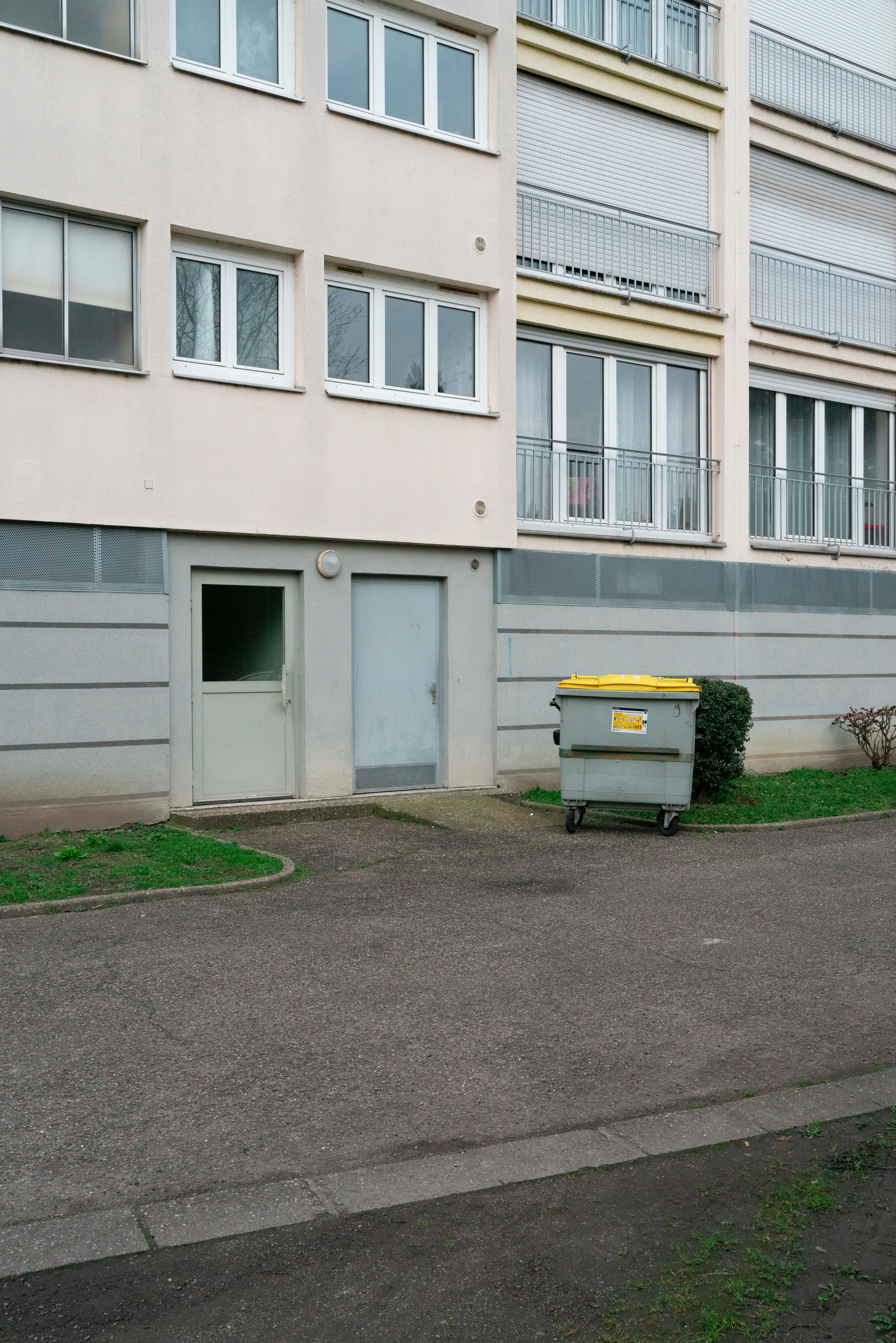 Yellow-Lidded Dumpster at the Edge of a Quiet Apartment Block