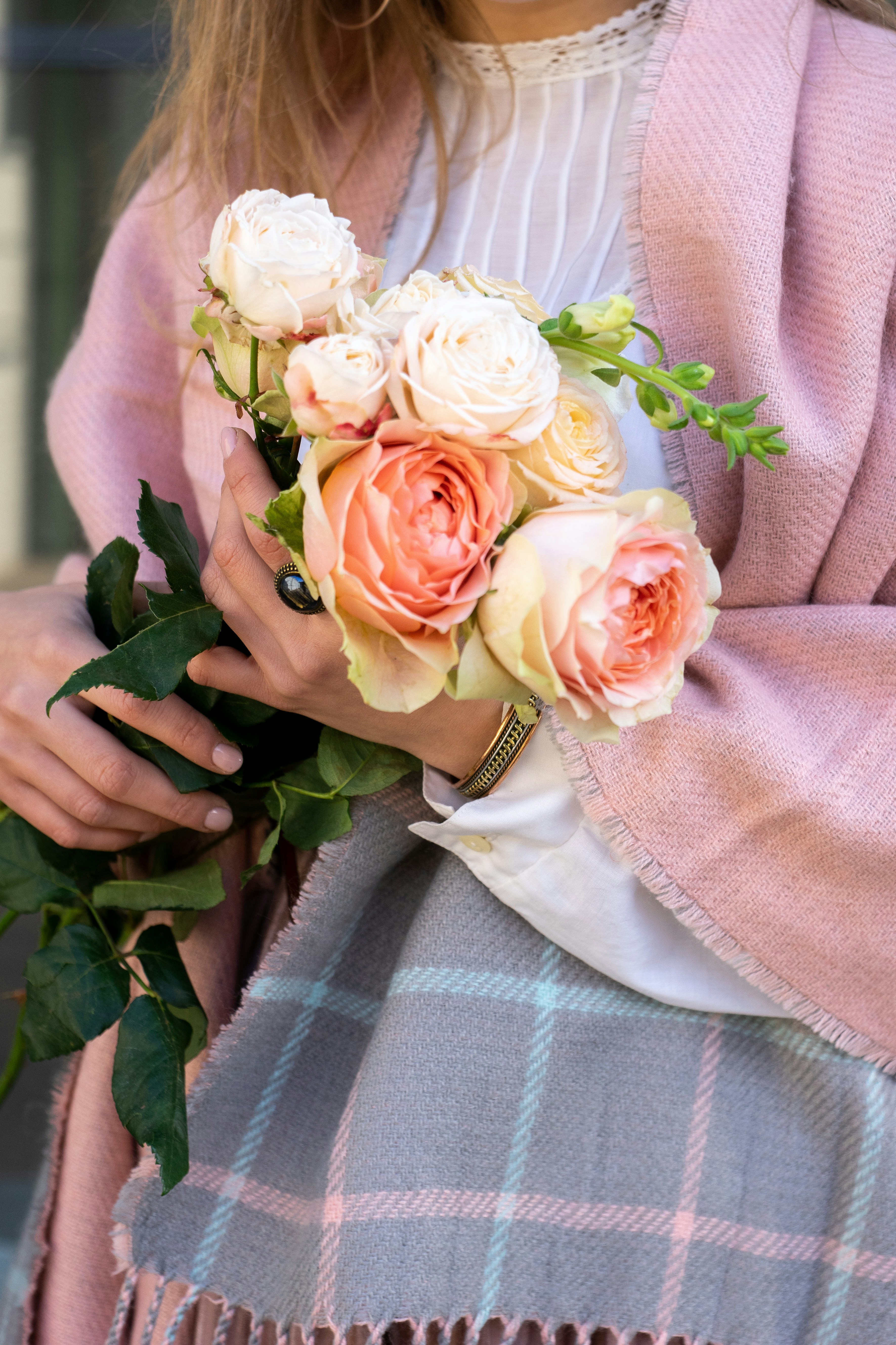 Bouquet of blush roses in soft pastel cardigan embrace