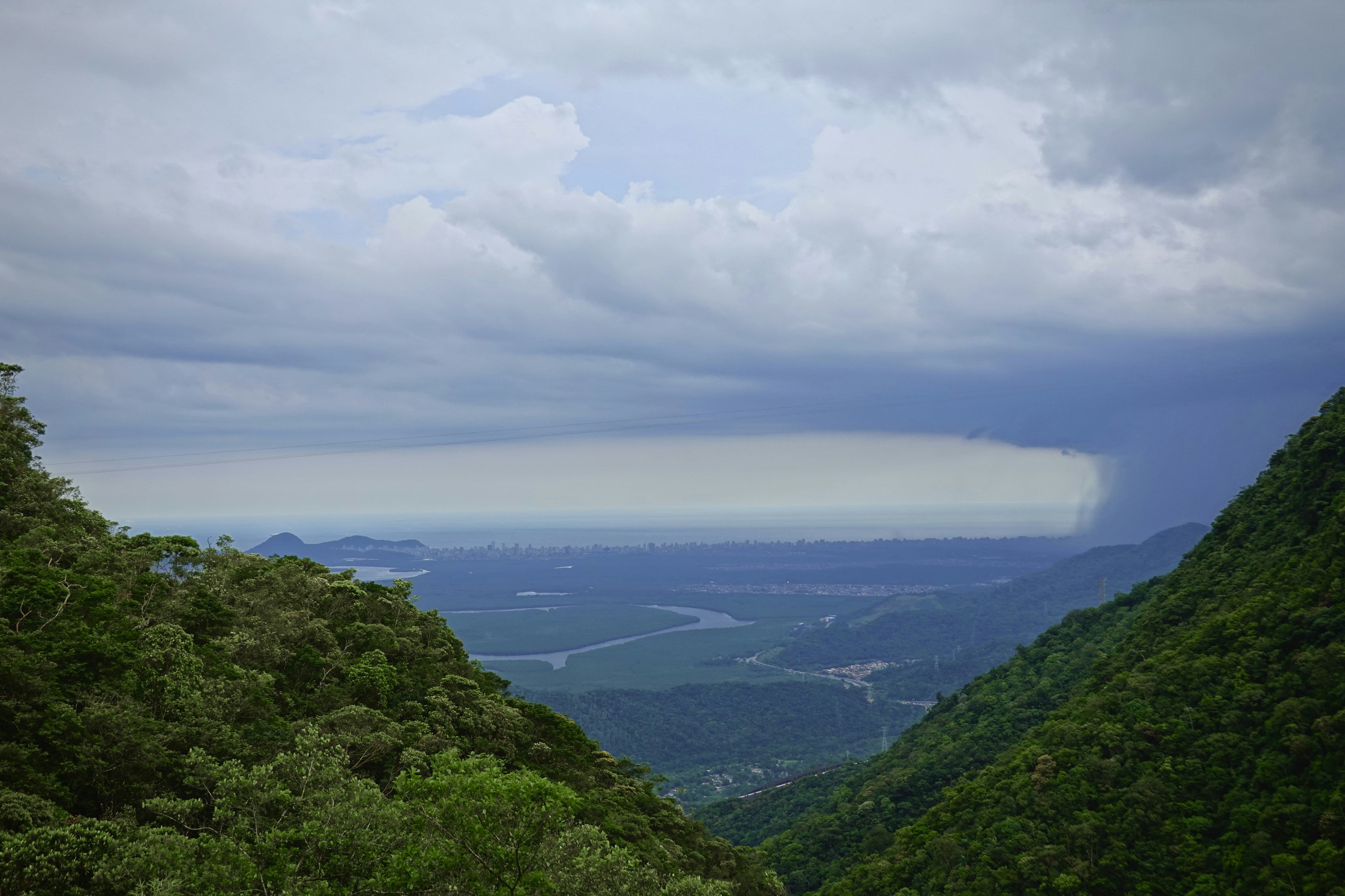 Cloud shelf over a valley: a dramatic horizon framed by green cliffs