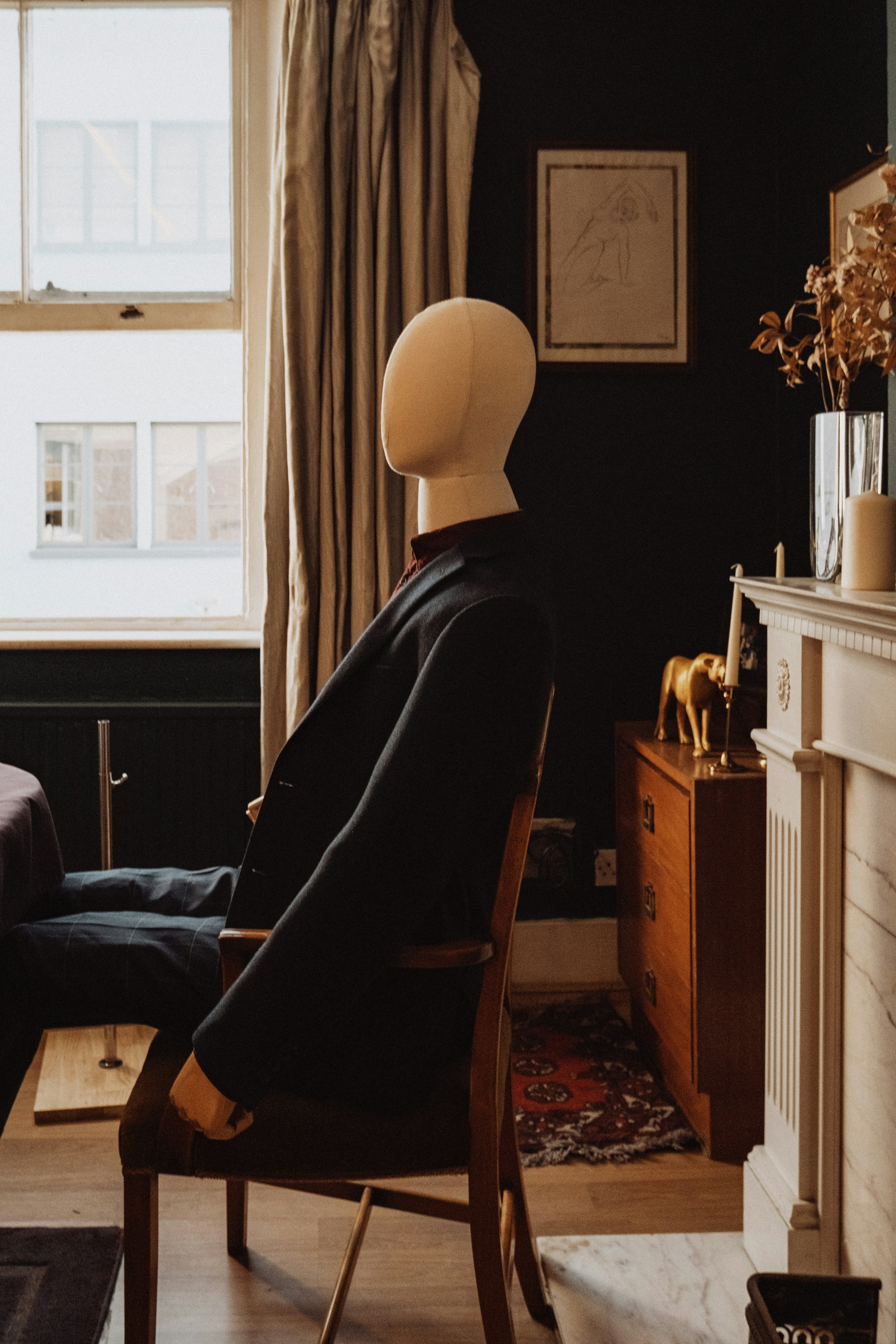 A mannequin sitting in a chair in front of a window photo – Free ...