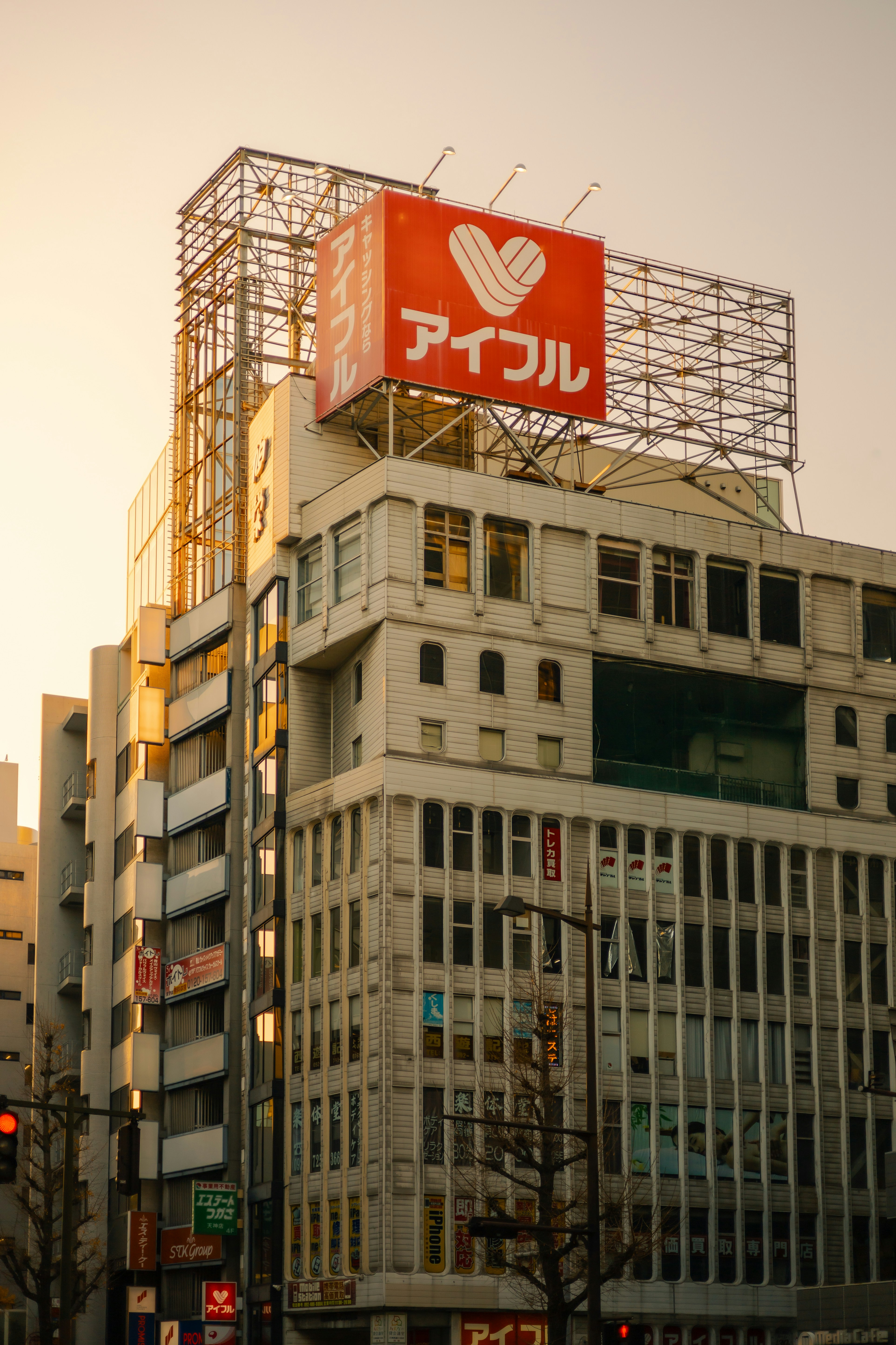 Red Billboard Crowned Over a Grid-Fronted Tower at Dusk