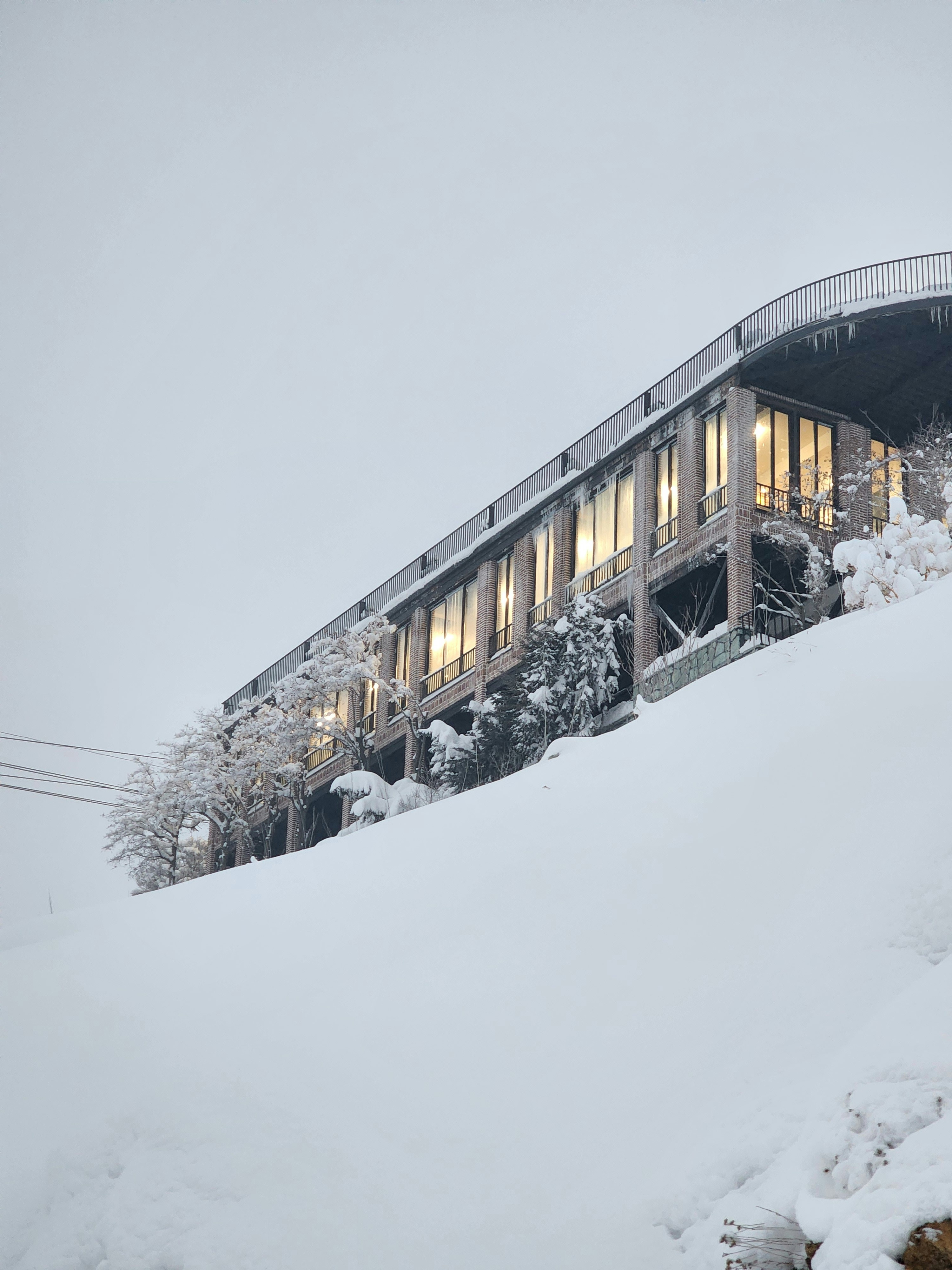 Glowing Windows on a Snowbound Lodge Clinging to a Sloped Ridge