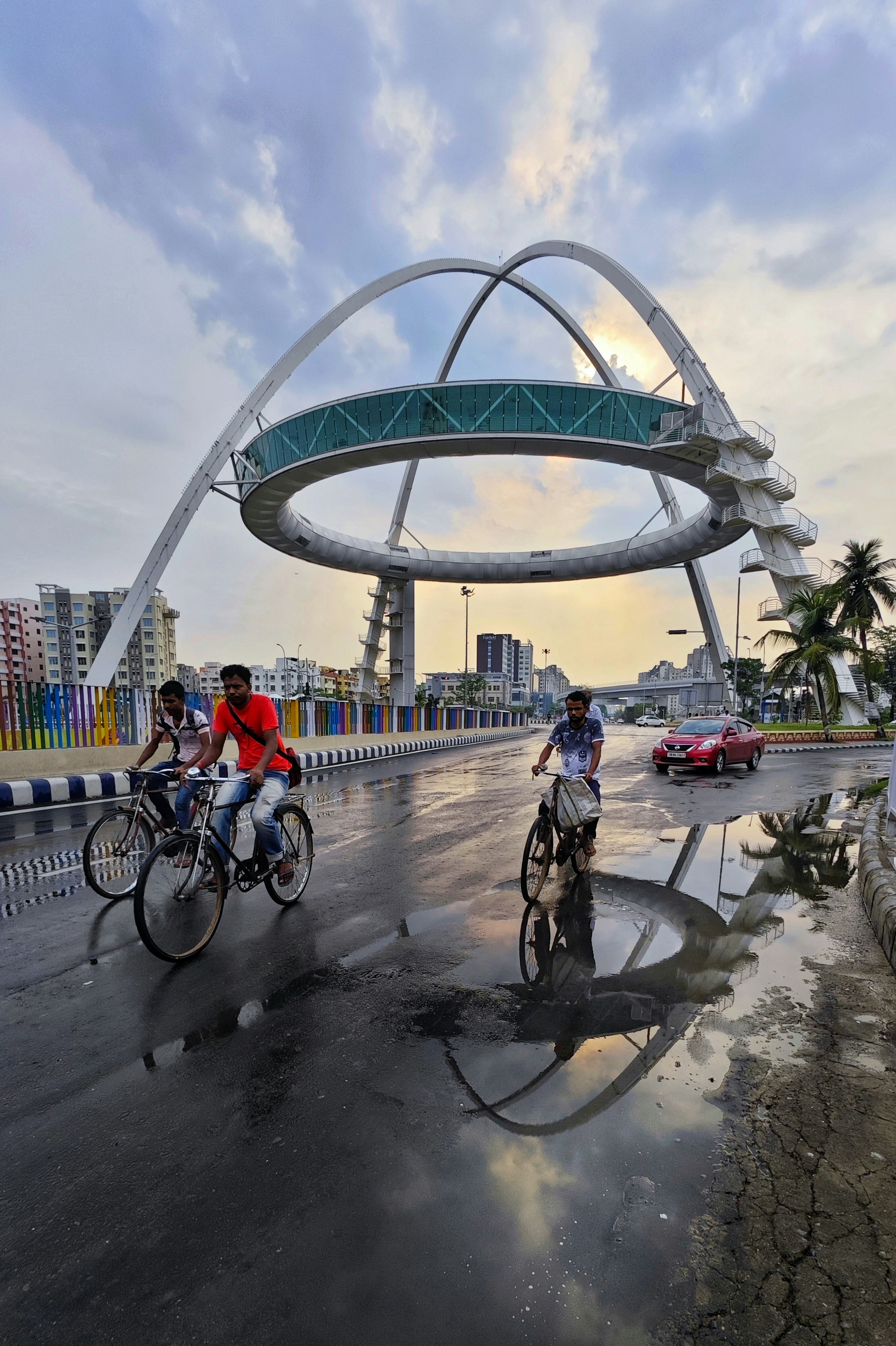Ringed Arch in Rain: Cyclists Beneath a Modern Loop Bridge