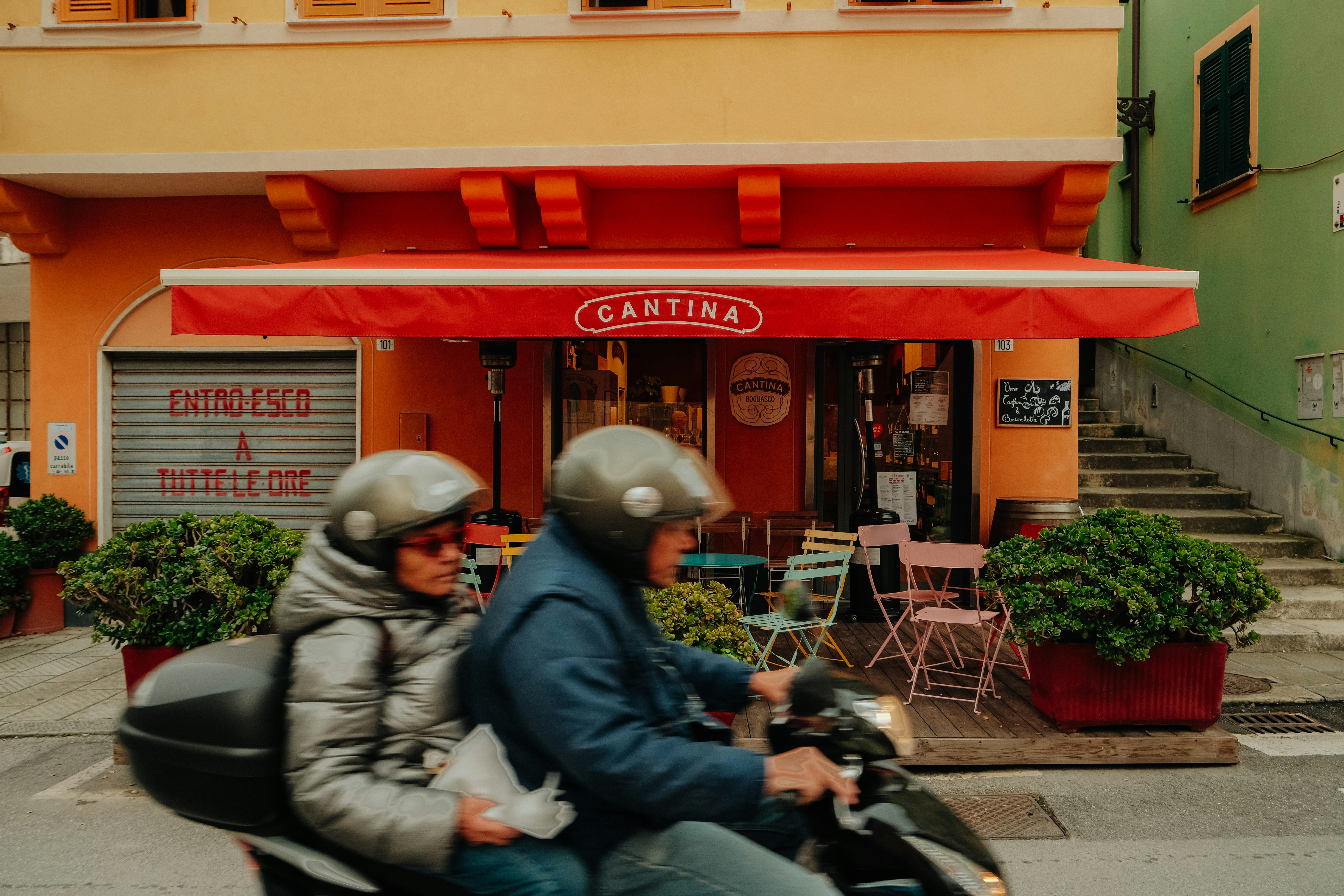 Scooters in Motion Past a Colorful Café