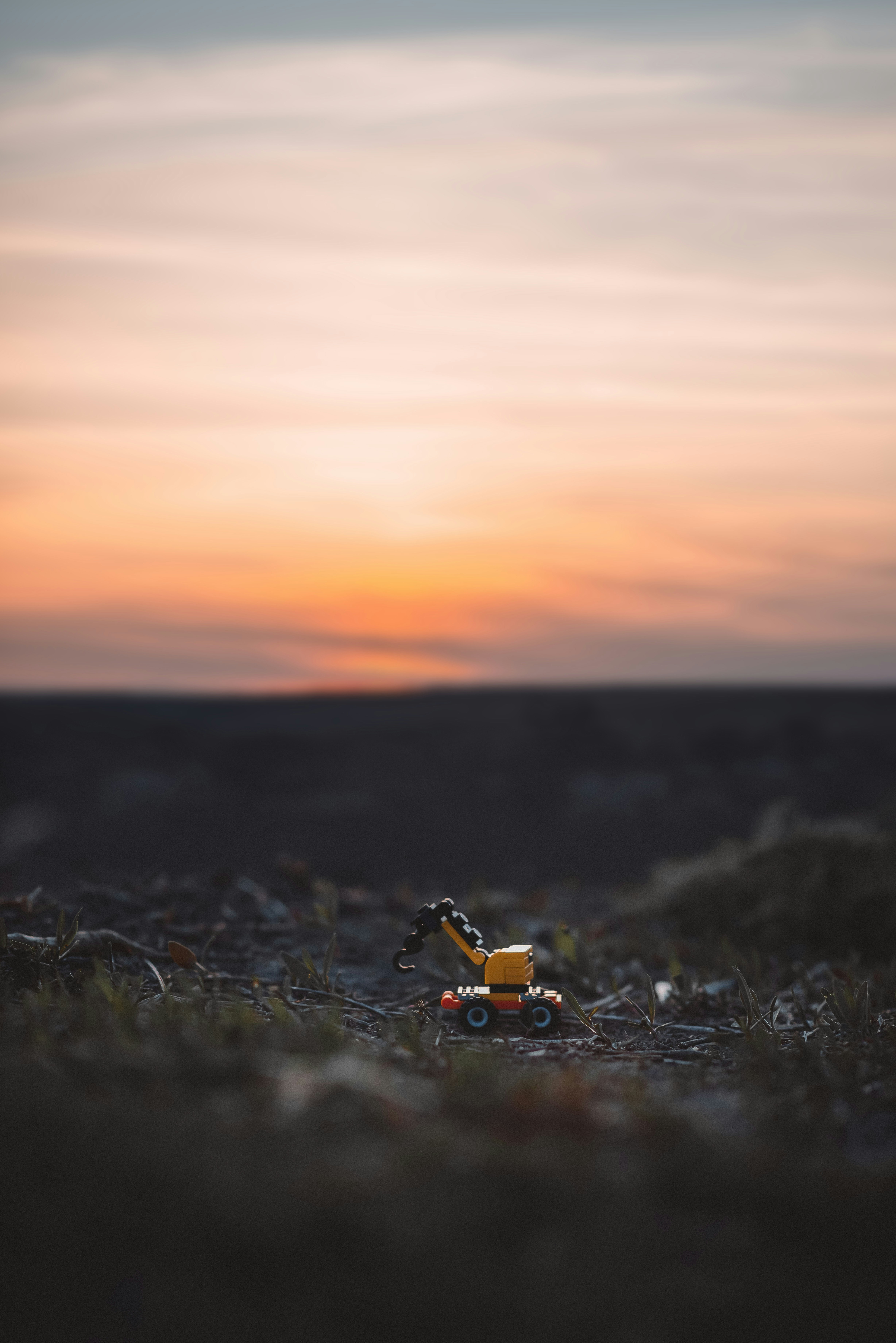 Dusk's Small Sentinel: Toy Excavator at the Horizon's Edge