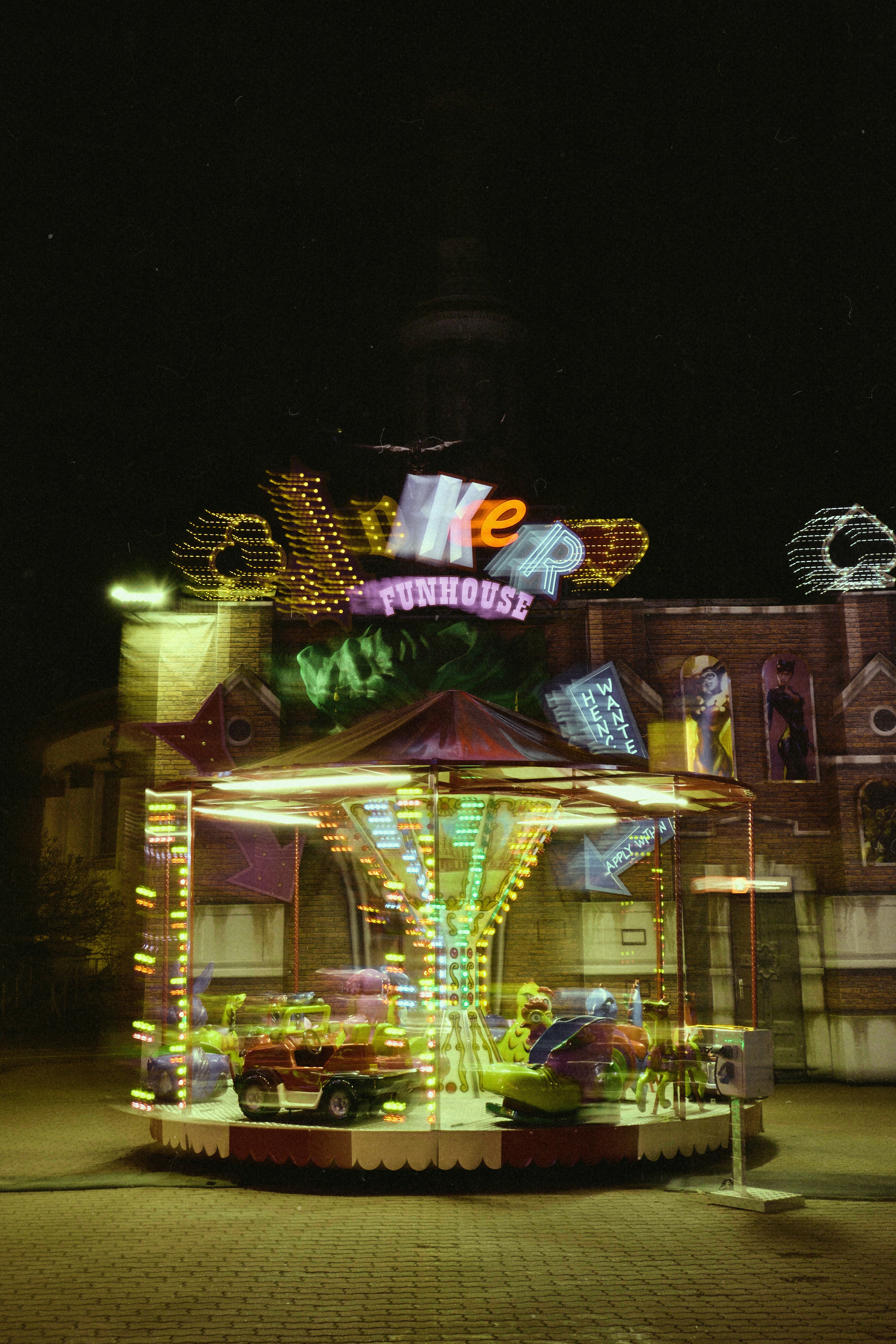 Neon Carousel in a Night-Quiet Square: Light Trails Over a Brick Facade