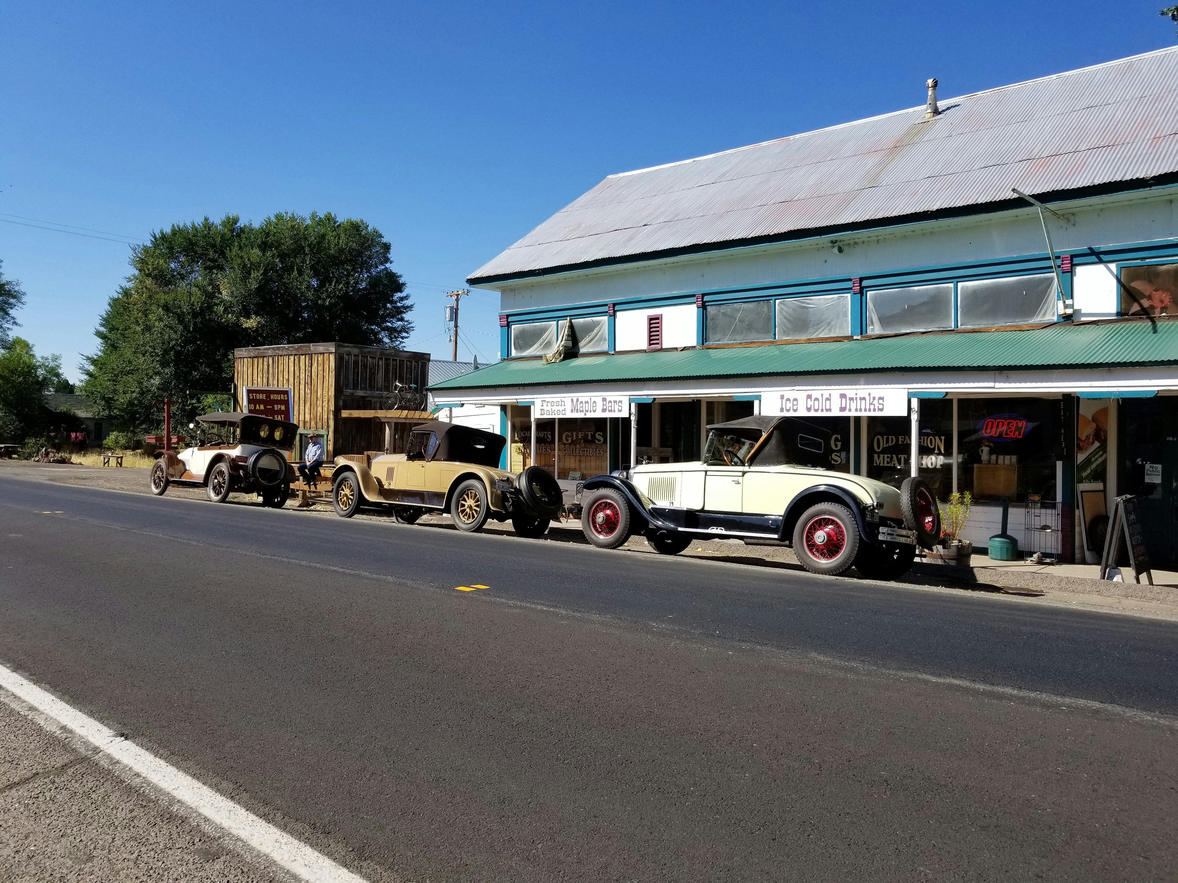 Sunlit Row of Vintage Automobiles by a Turquoise Main Street Storefront