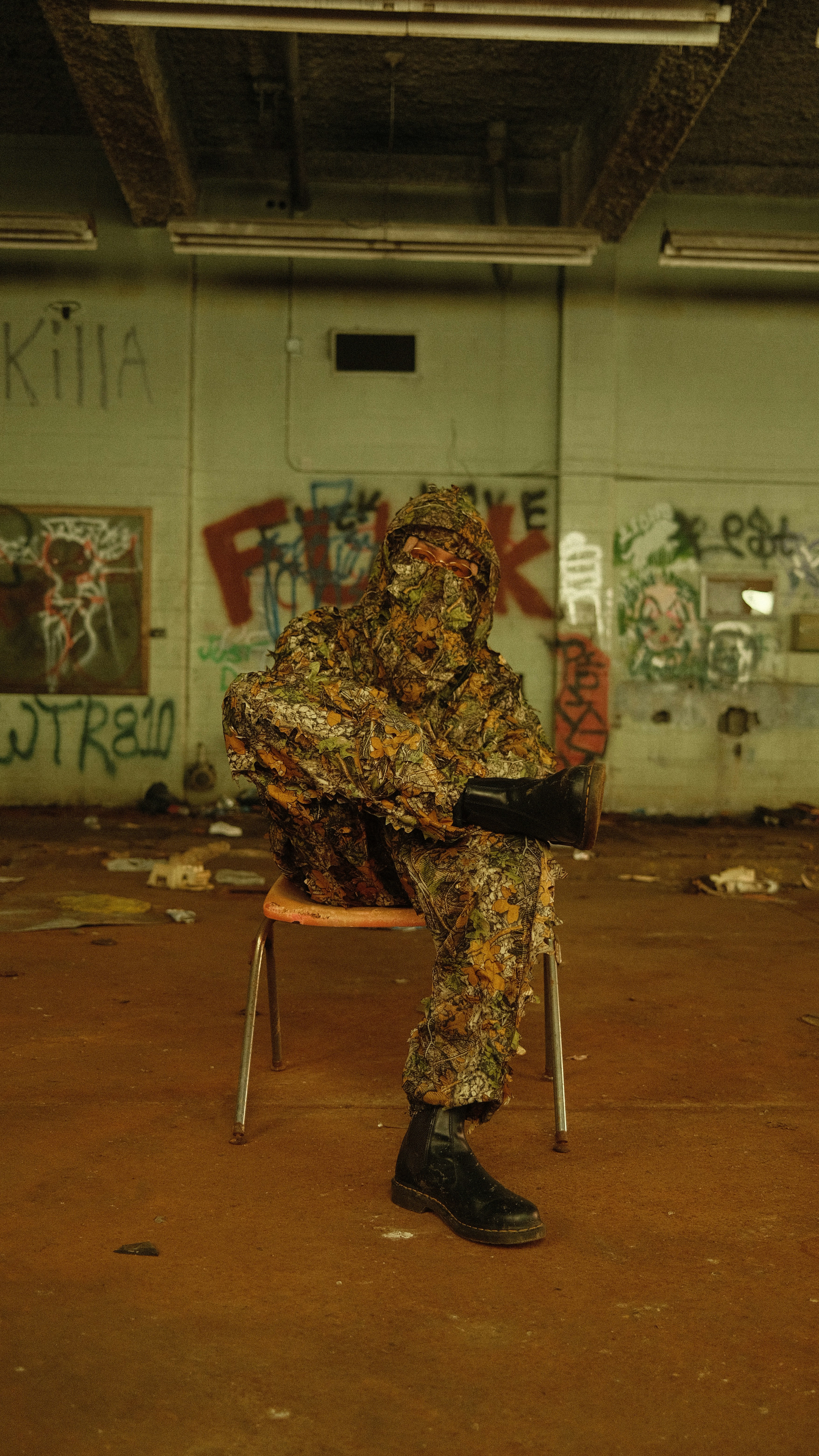 Leaf-Cloaked Figure in a Graffiti-Laced Concrete Vault