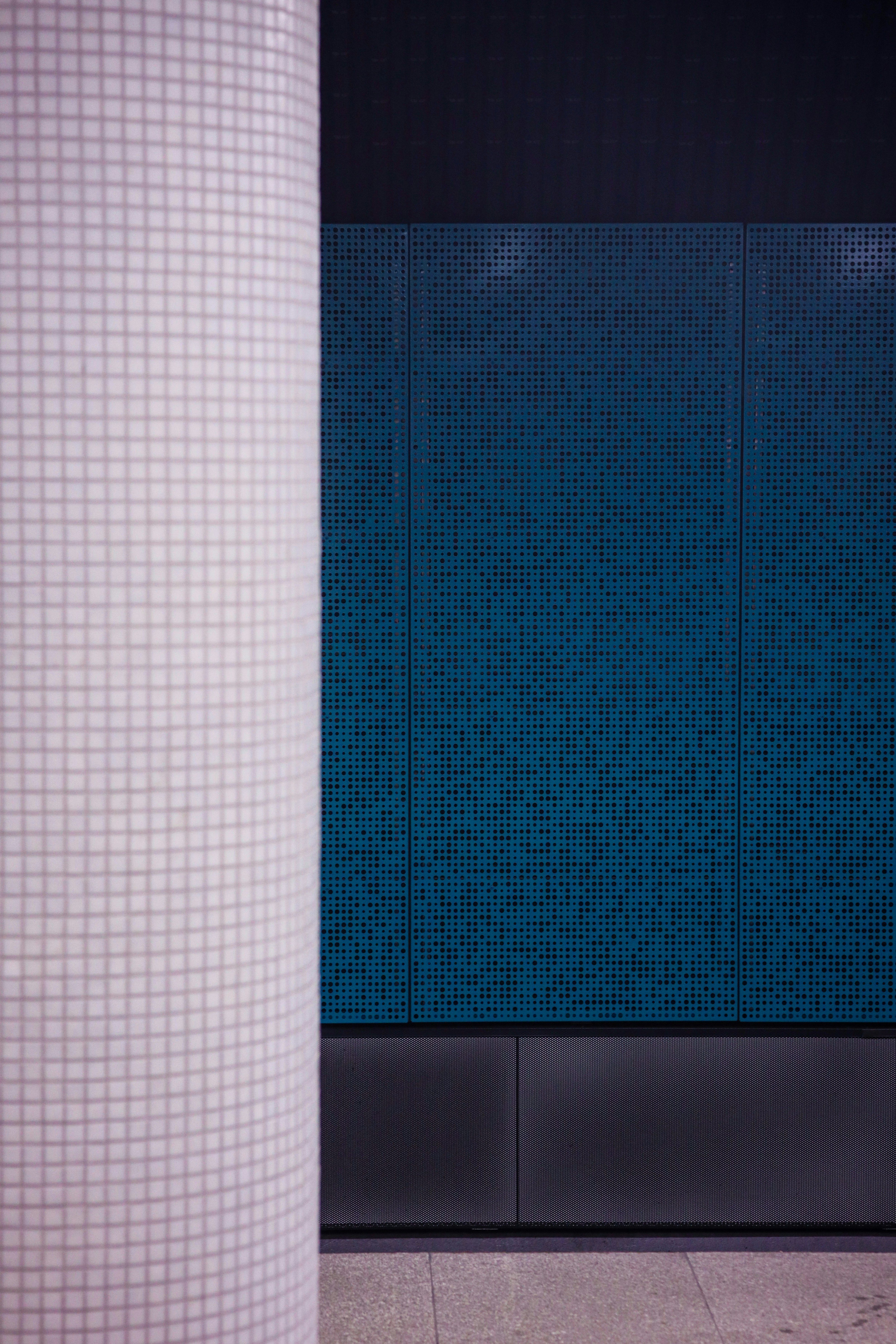 Threshold of Tiles: White Column Meets Teal Mosaic Facade