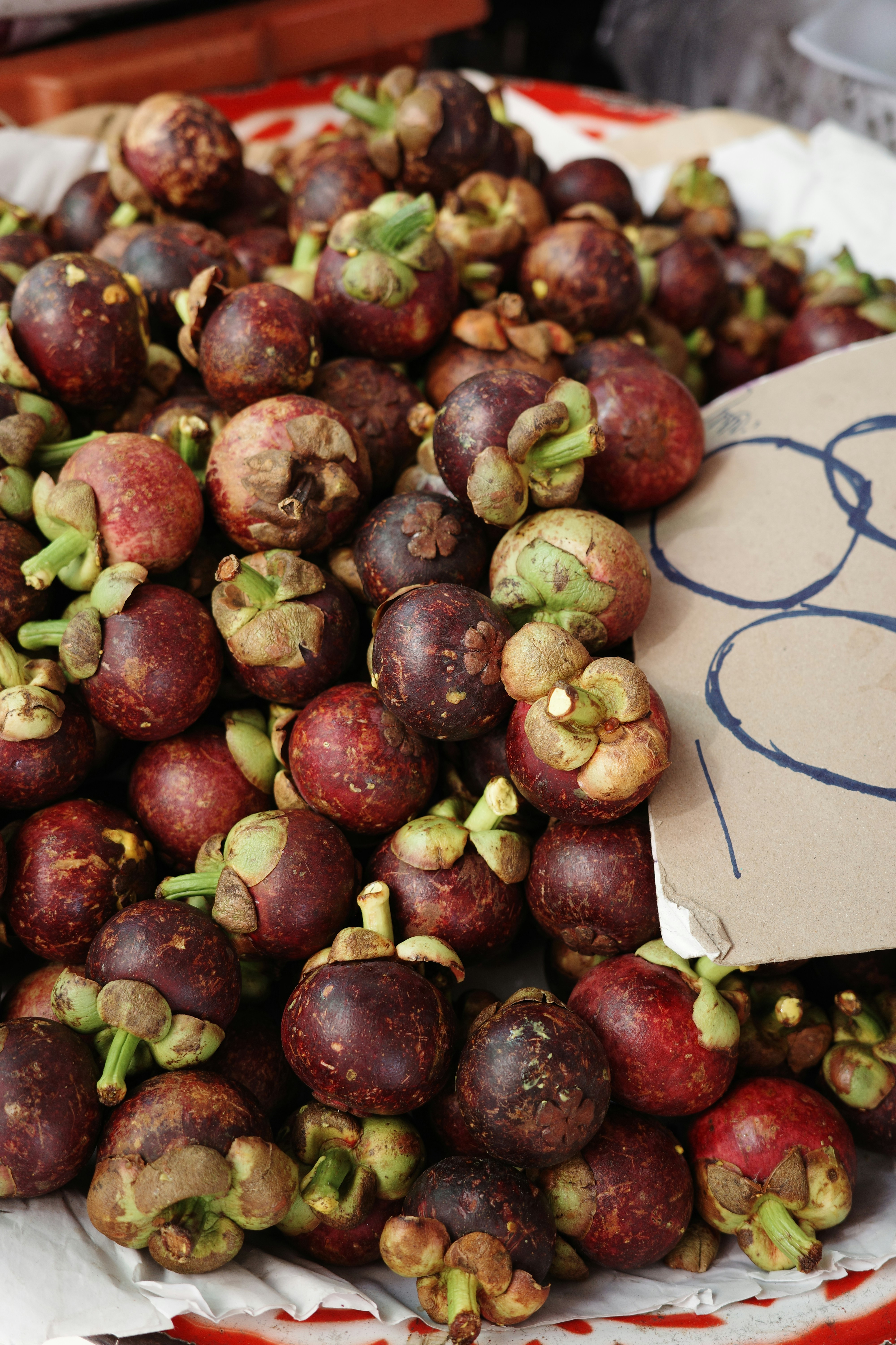 Fresh mangosteens piled high at a vibrant street market.