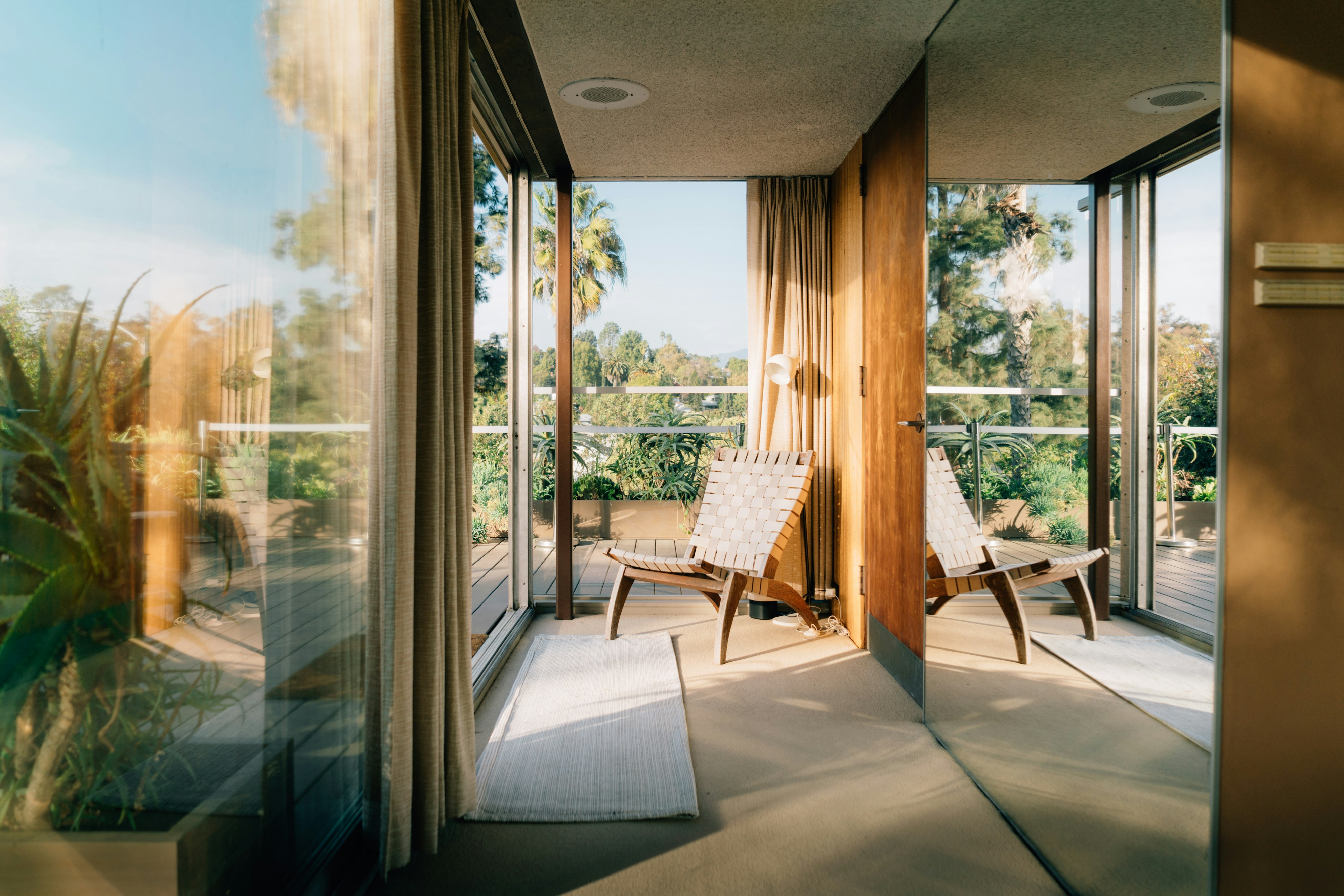 Two chairs bathed in sunlight by a glass door, with reflections creating a mirrored effect.