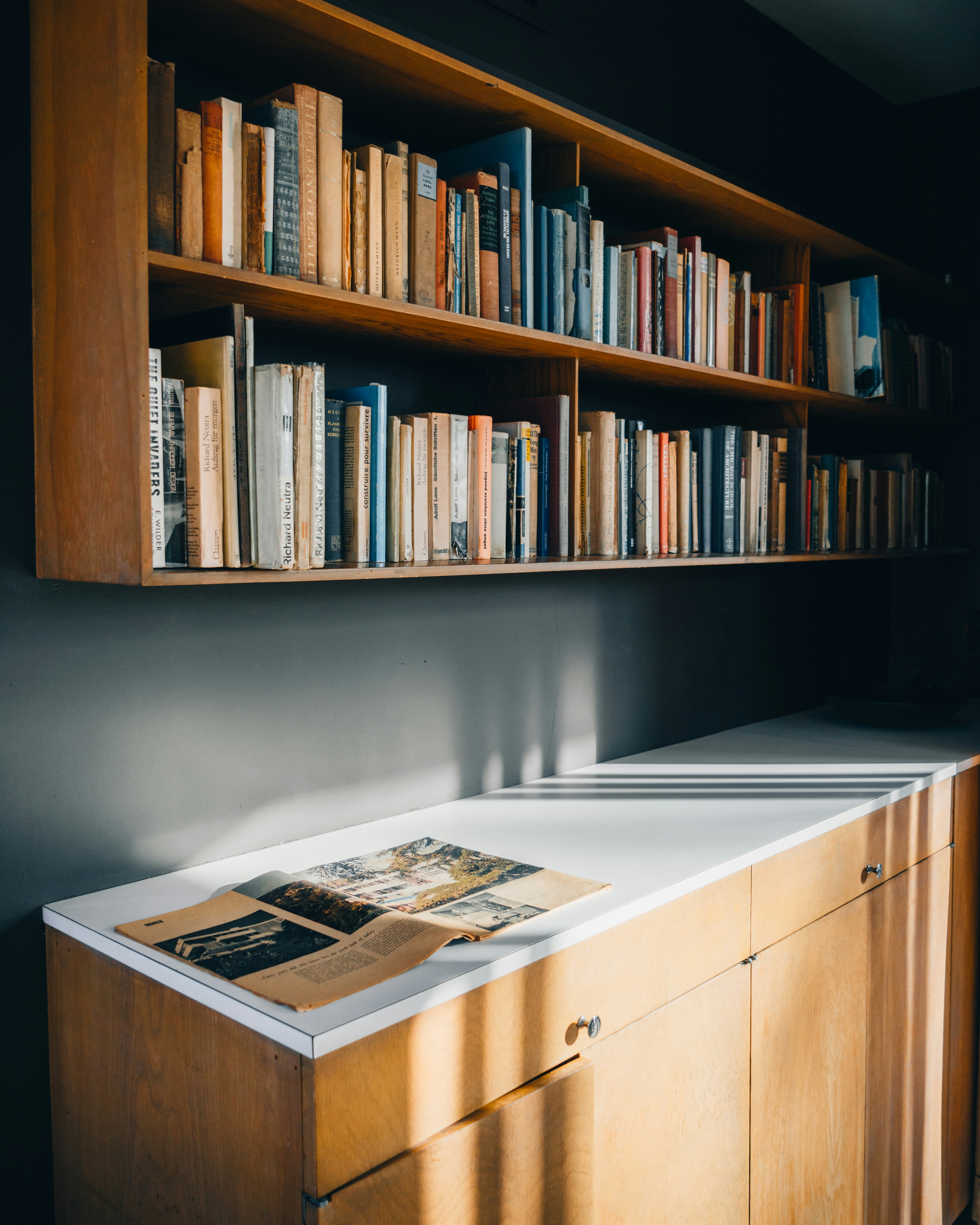 A bookshelf filled with lots of books next to a white counter photo ...