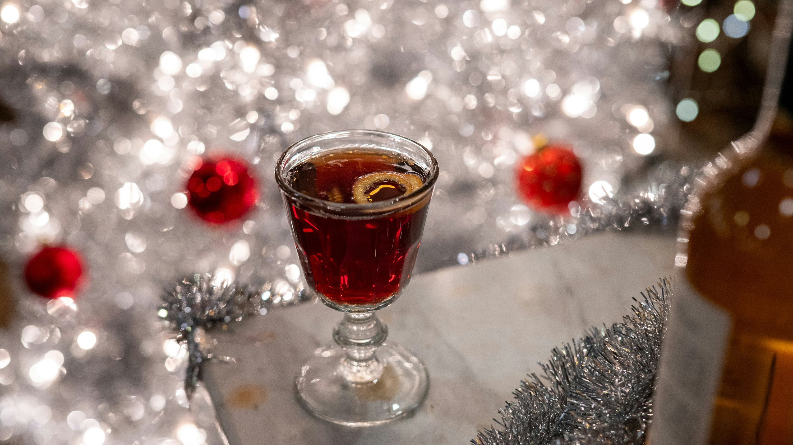A Christmas cocktail with a white Christmas tree background.