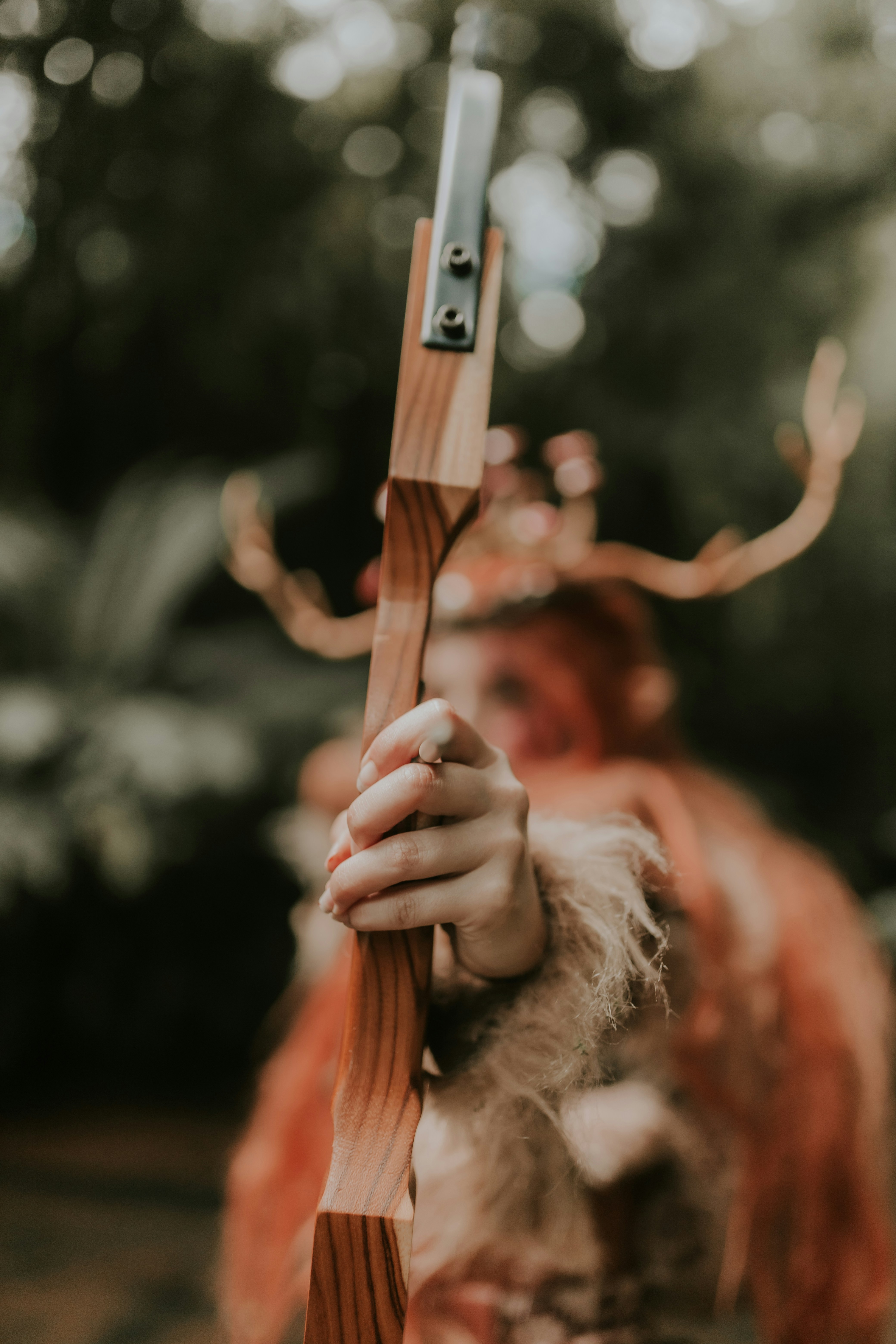 Antlered silhouette grips a carved bow in a sun-dappled forest