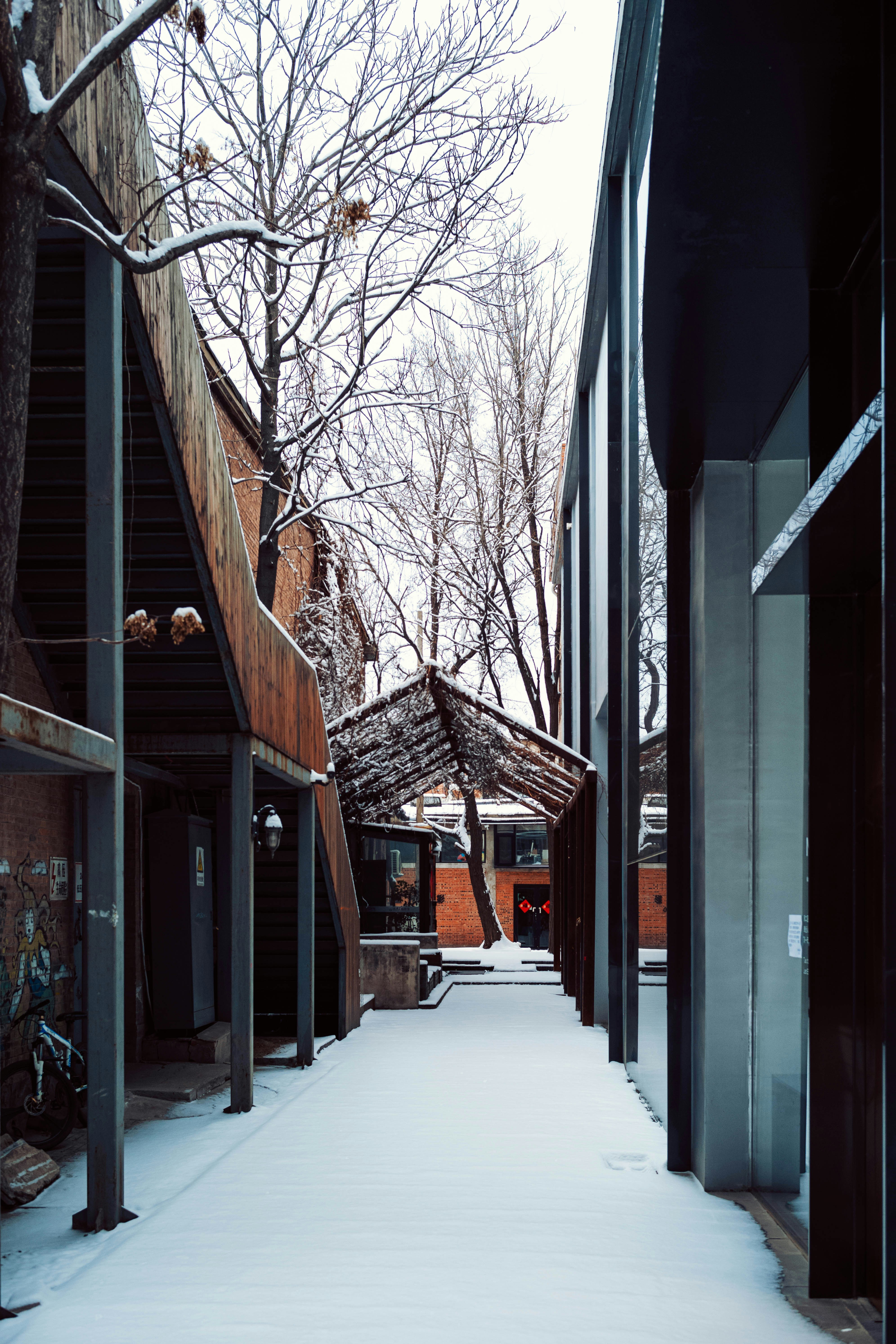 A snow covered walkway between two buildings photo – Free Street ...