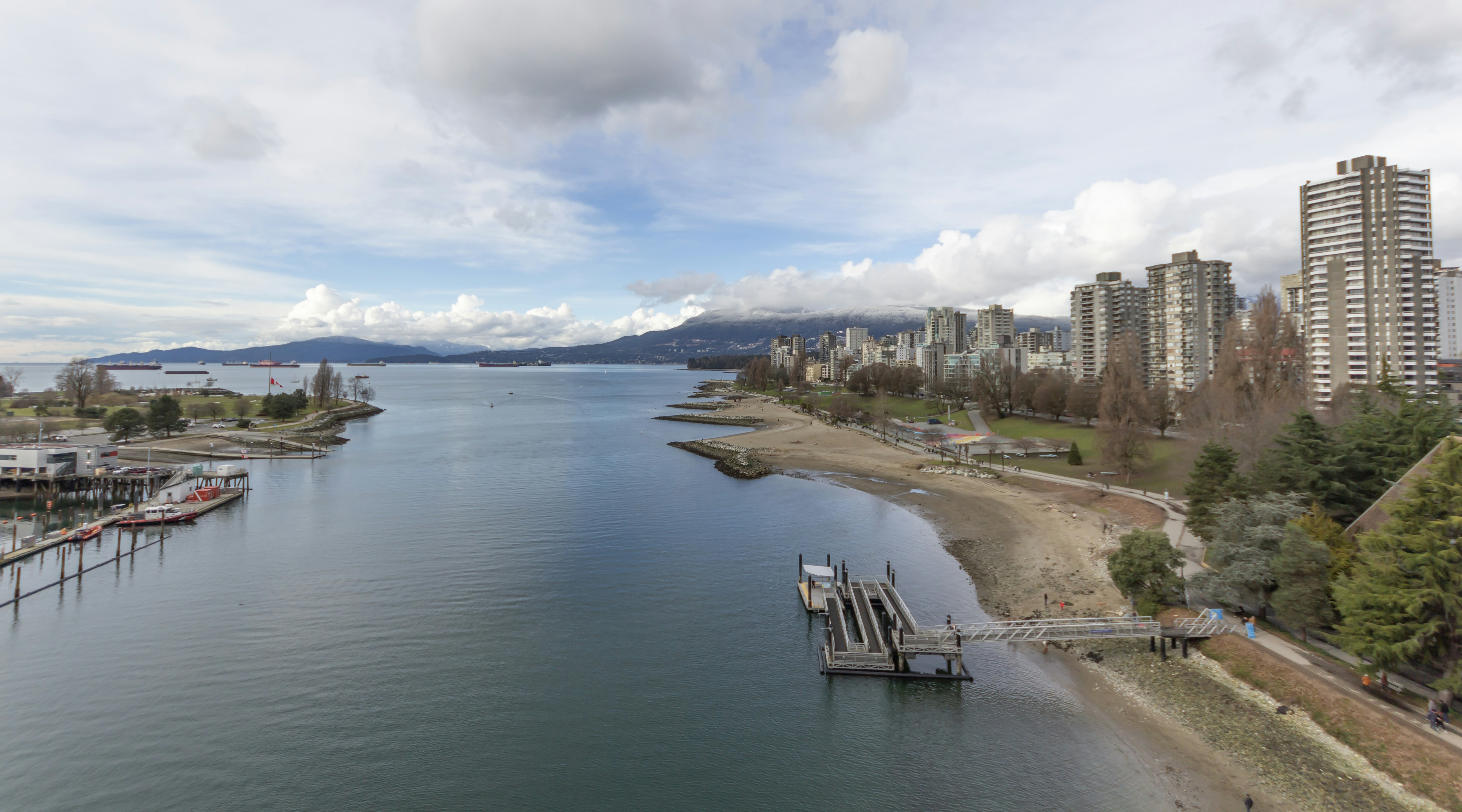 Harbor Lines: Aerial View of Docks, Waterfront High-Rise, and Distant Mountains