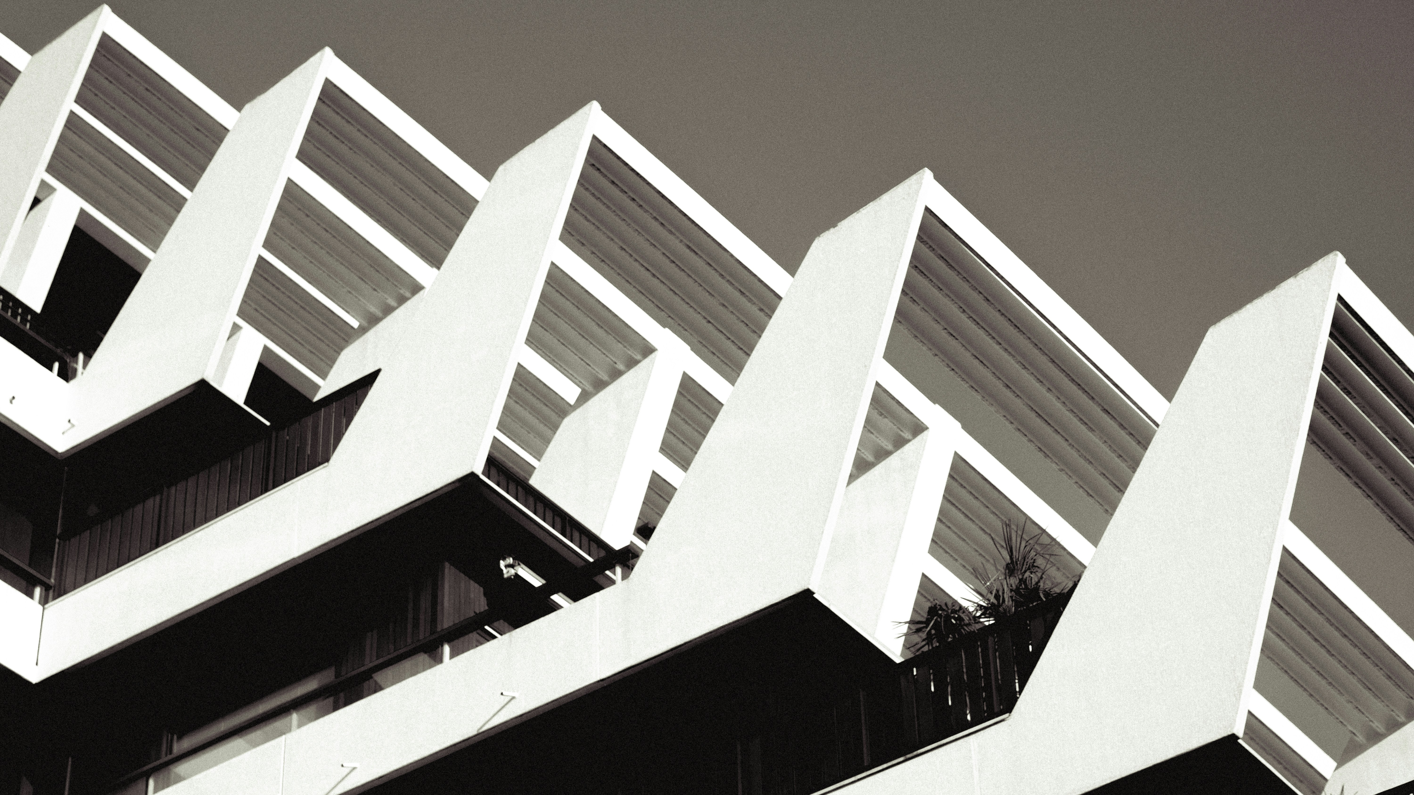 Modern architectural facade with angular white beams against a clear sky.