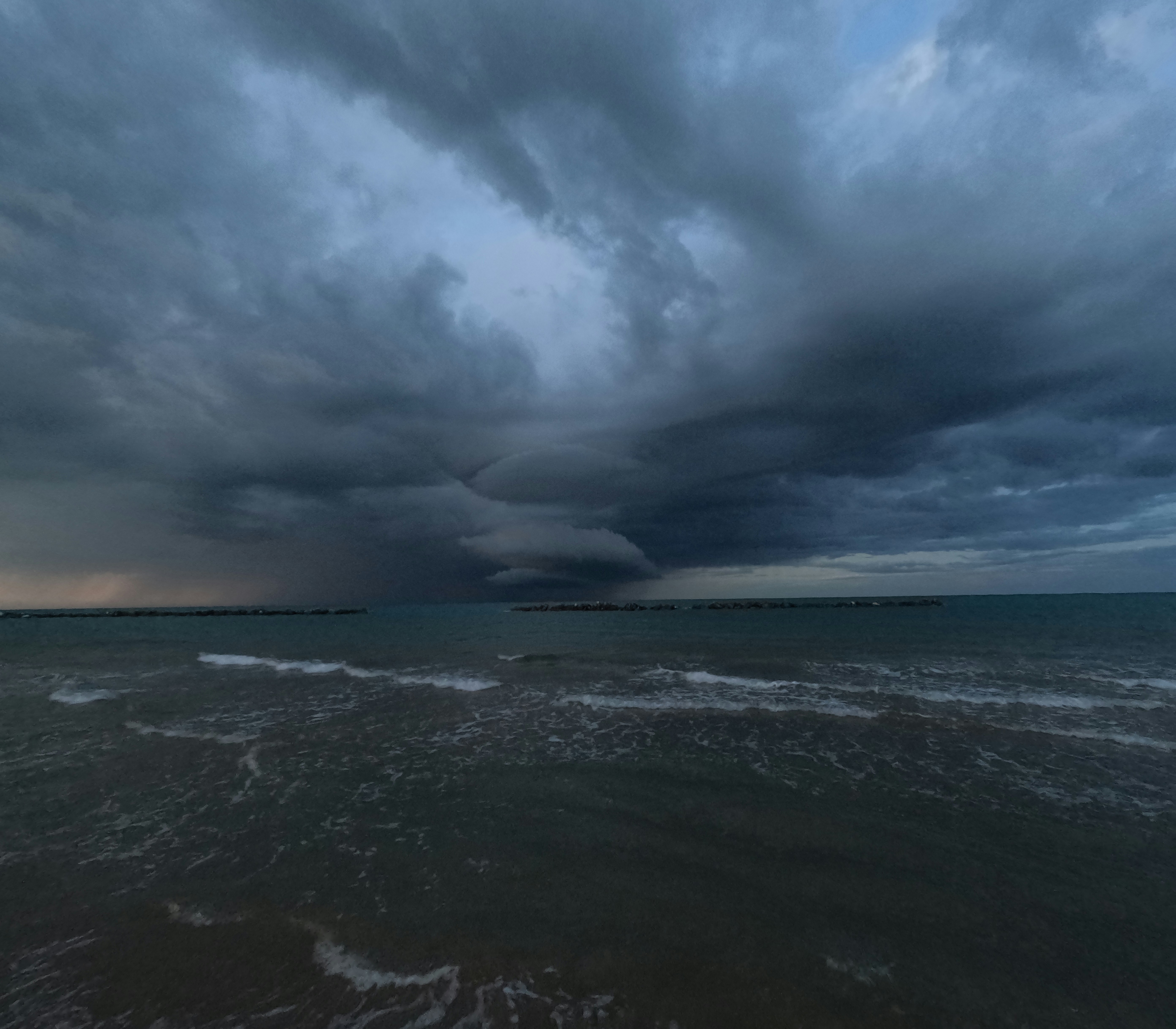 A storm moving across the sky over a body of water photo – Free ...