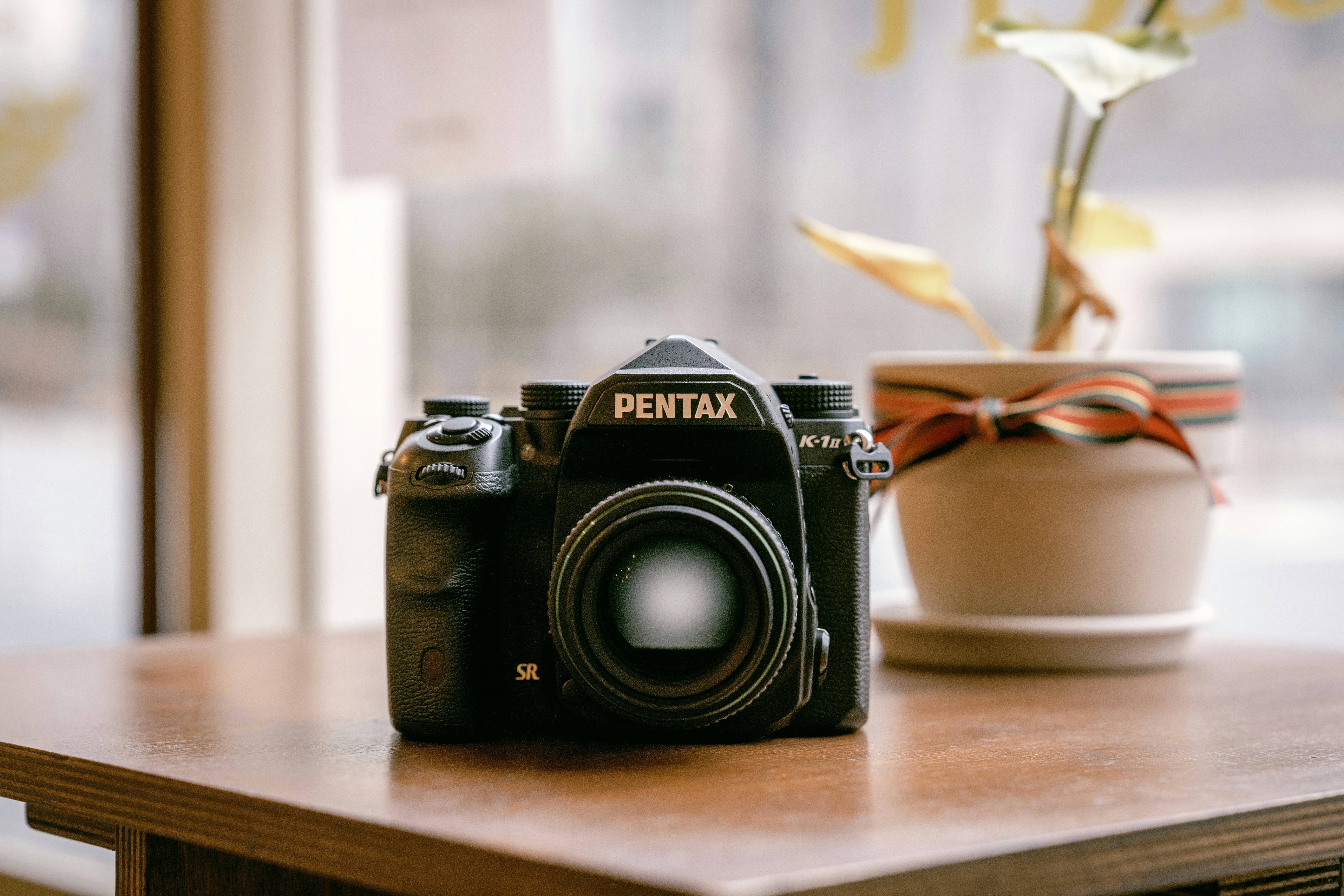 A camera sitting on a table next to a potted plant photo – Free Camera ...