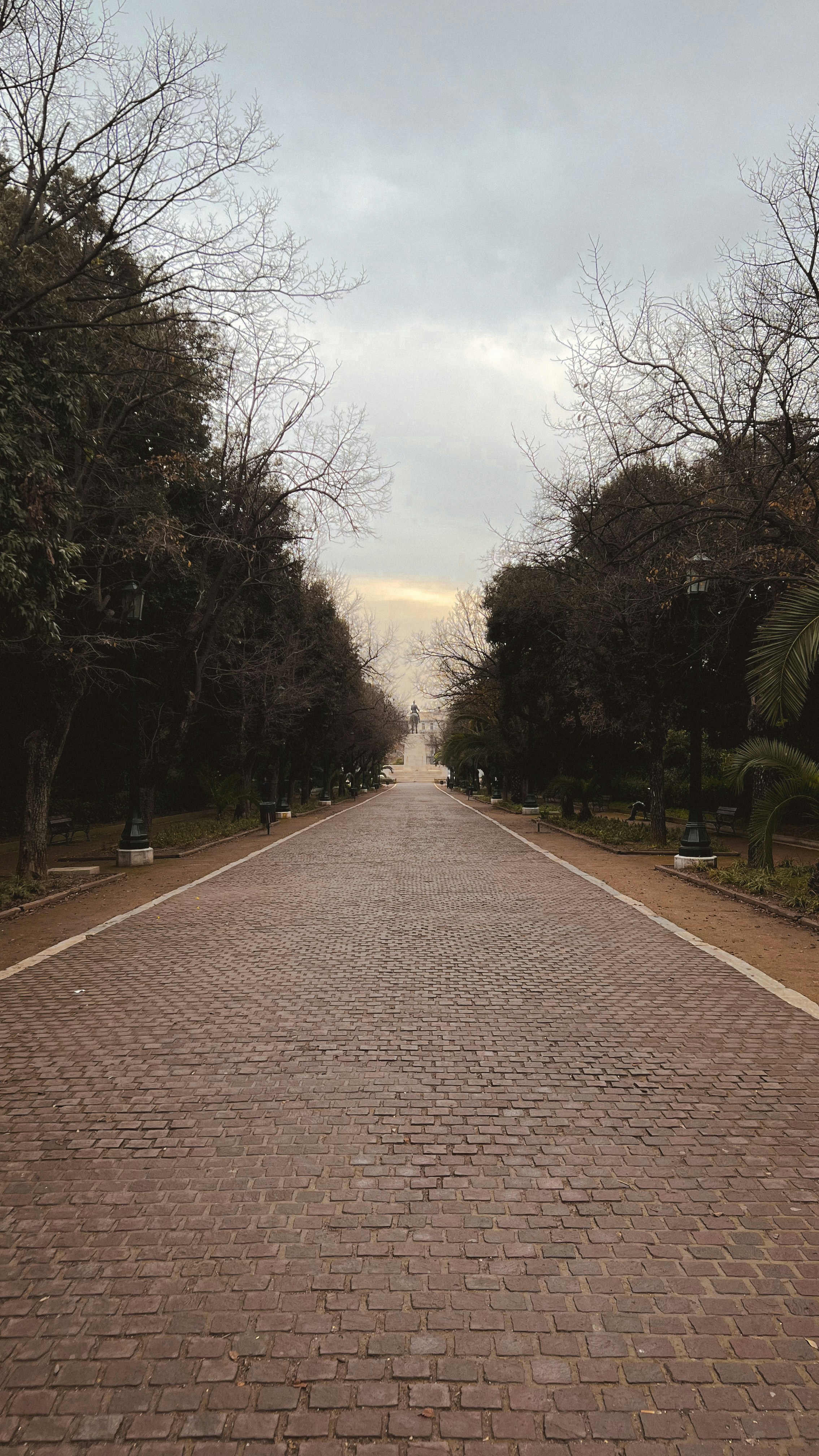 Cobbled Avenue Toward a Distant Statue