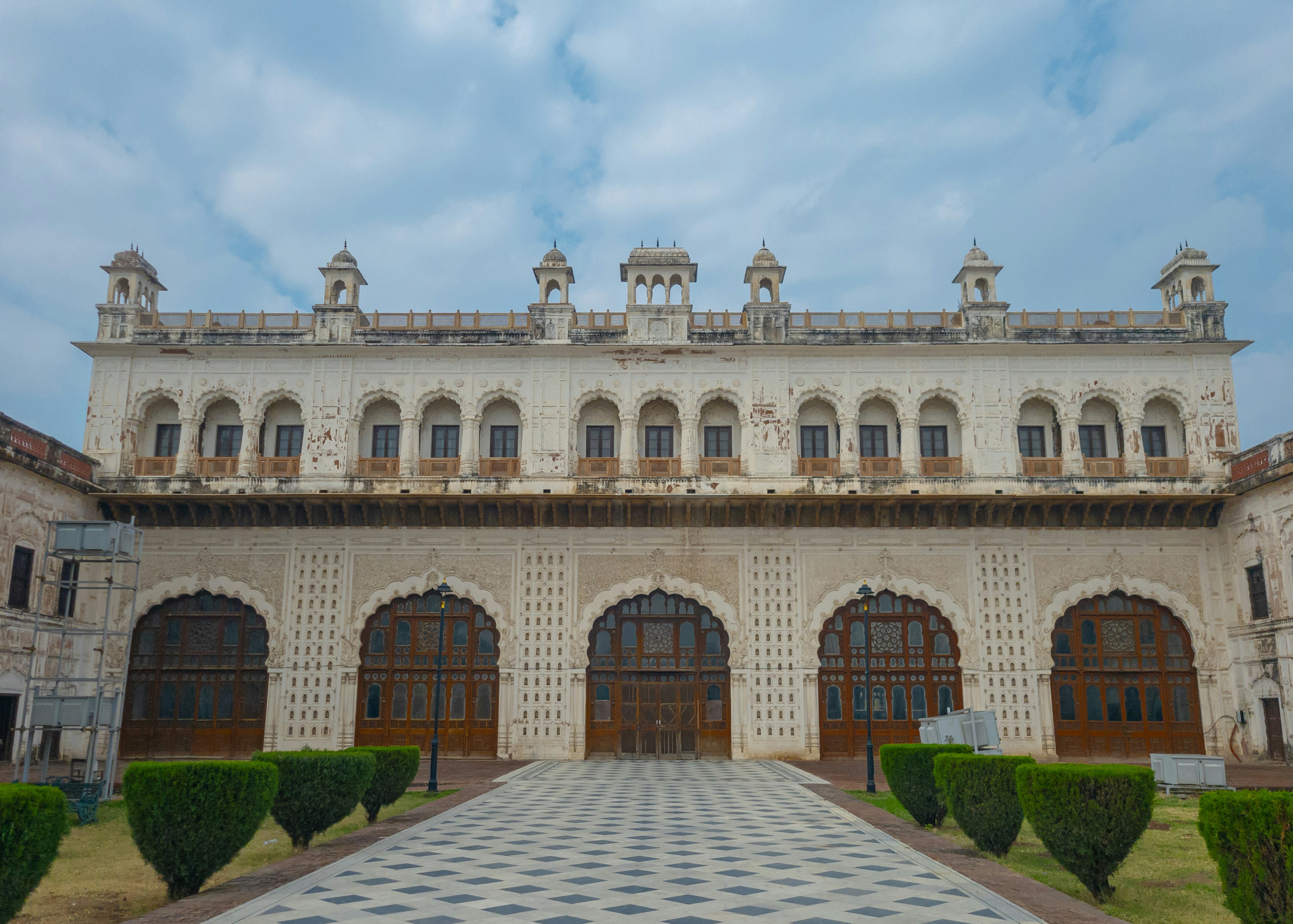 Grand historic building with arched entrances and detailed façade under a cloudy sky.