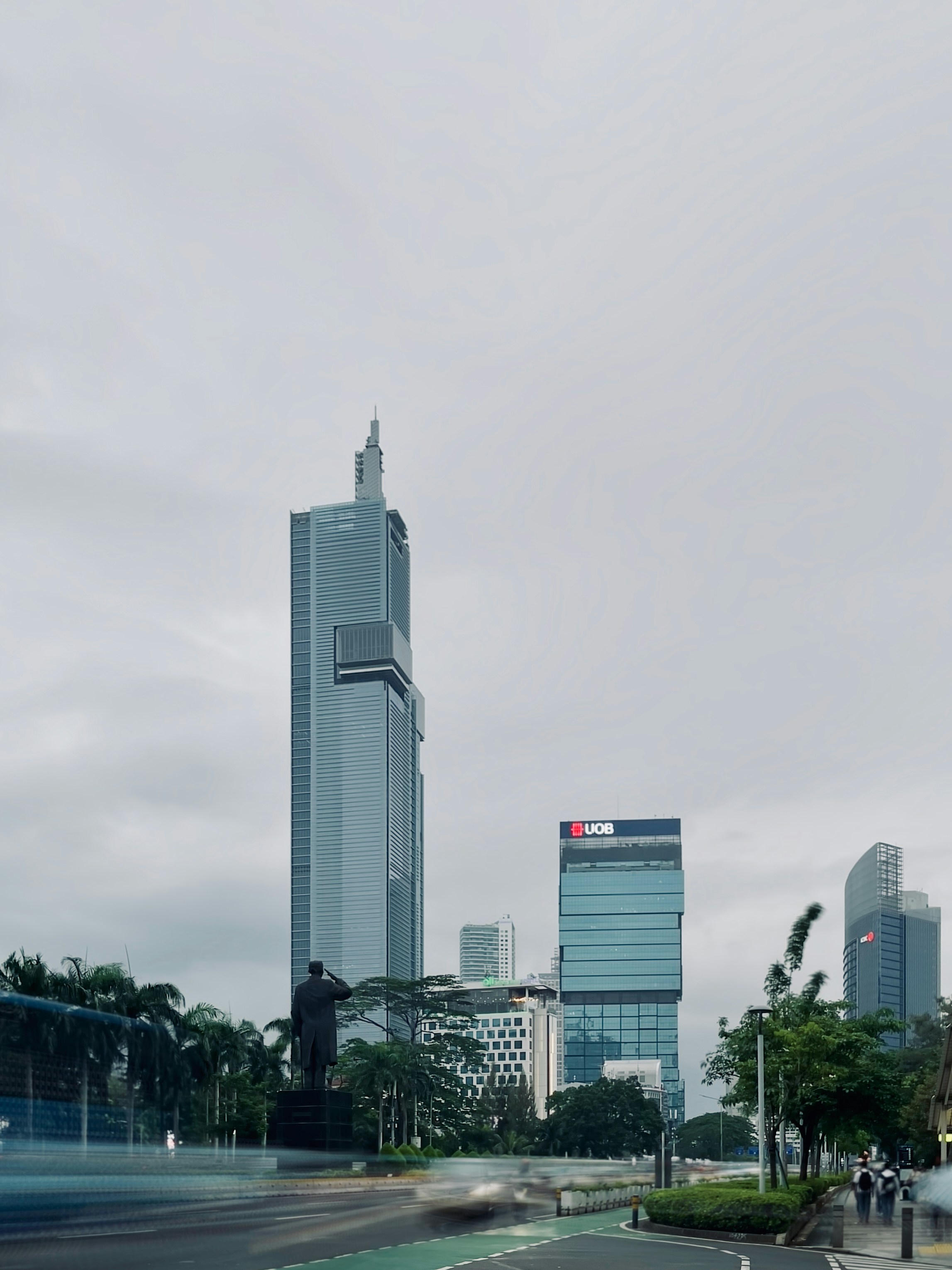 Monolithic Tower Under an Overcast Sky Framing a Busy Boulevard