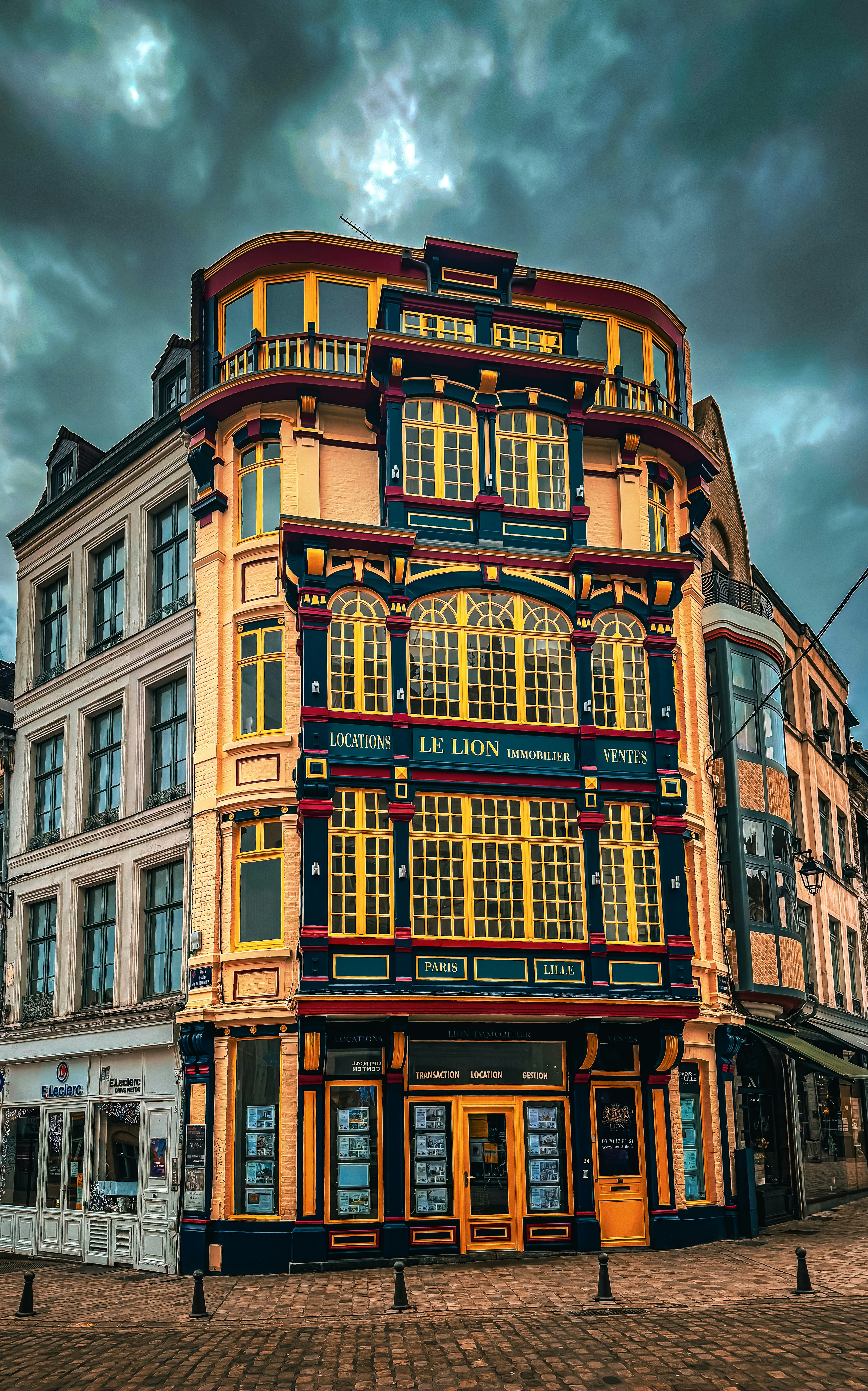 Le Lion of Lille: A Candy-Colored Corner Façade Beneath a Stormy Sky