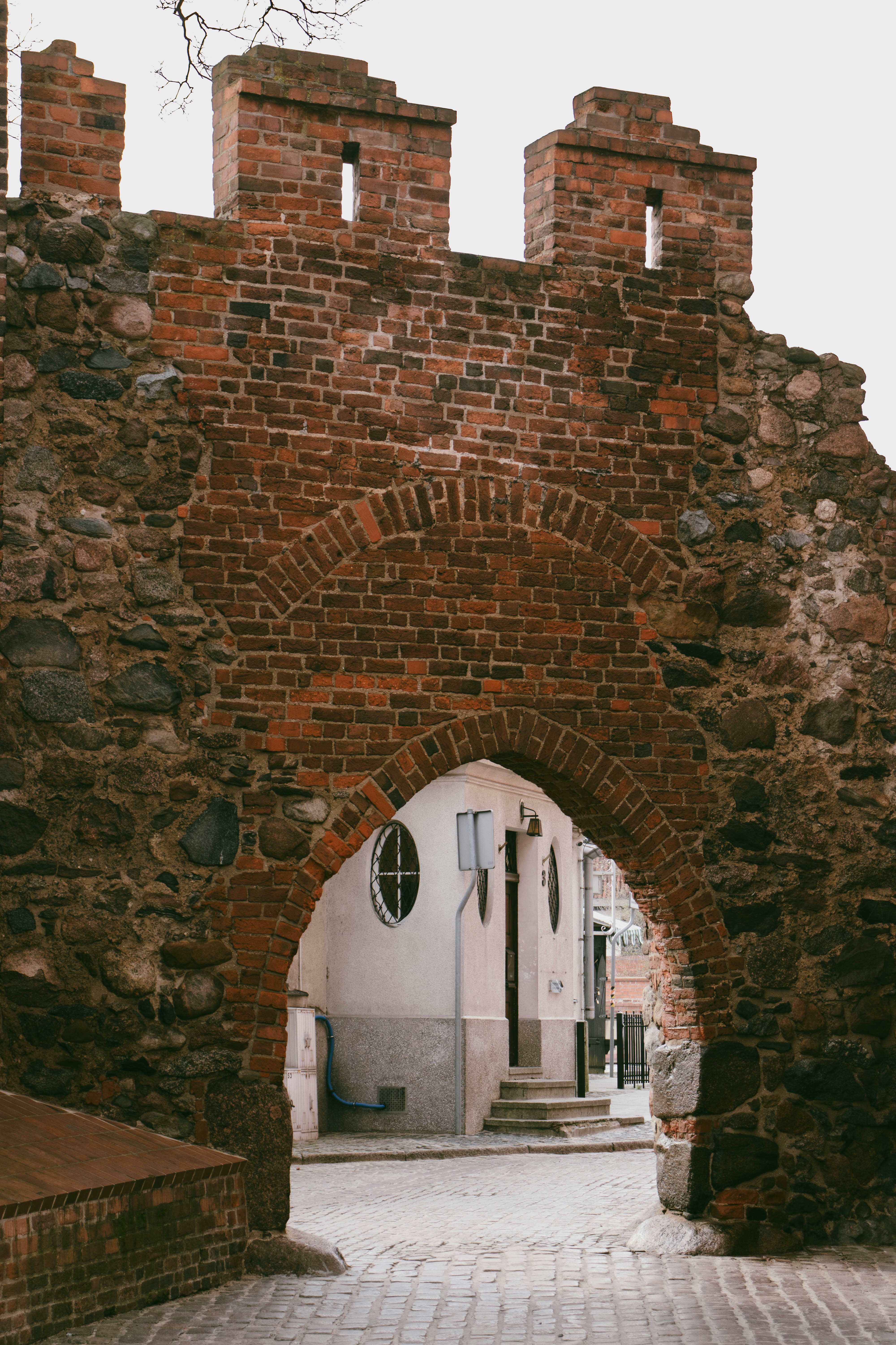 A Timeworn Brick Archway Opening onto a Cobblestone Street