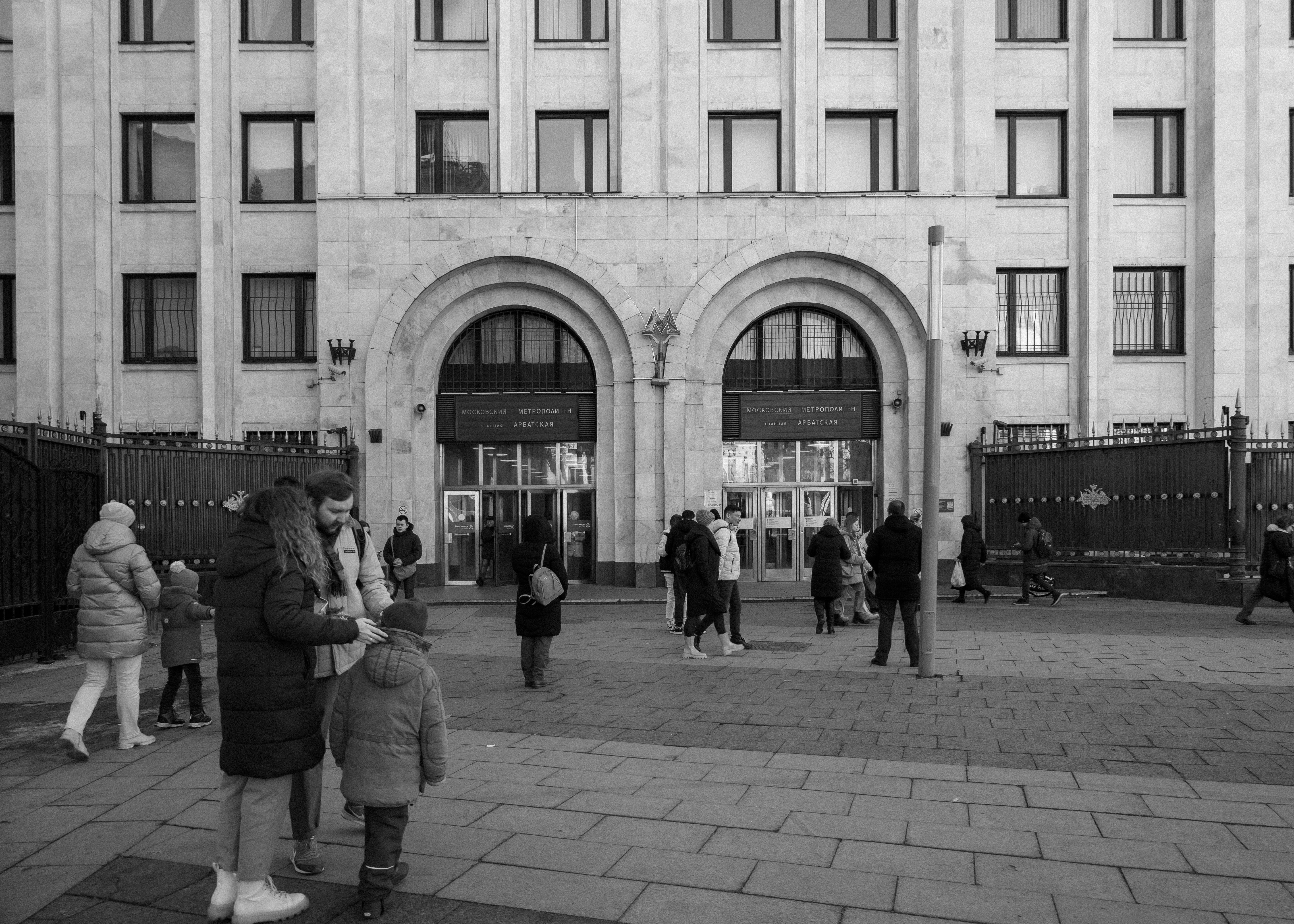 Three Archways, One City Square: Pedestrians in a Monochrome Moment