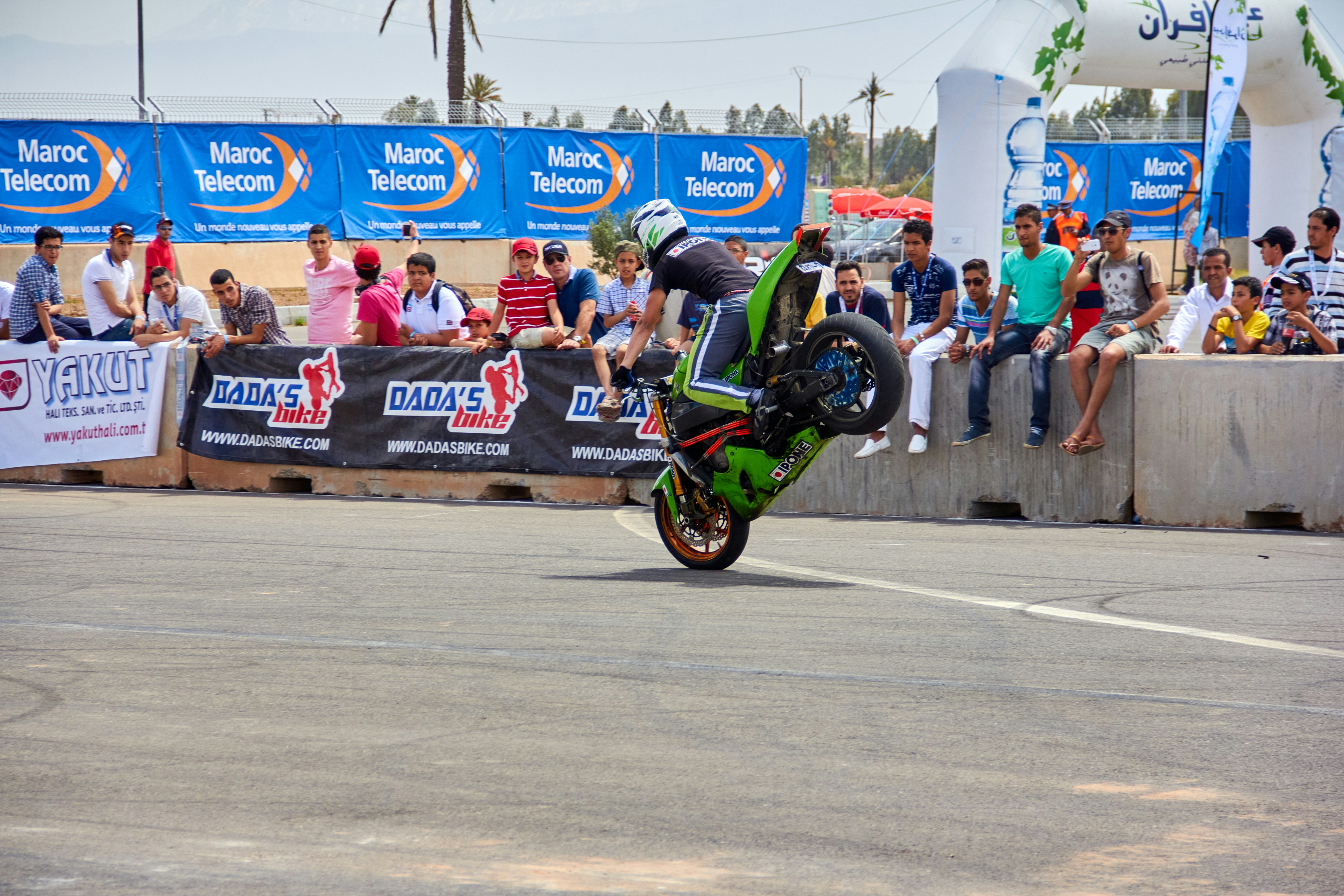 A person on a motorcycle doing a wheelie in front of a crowd photo ...