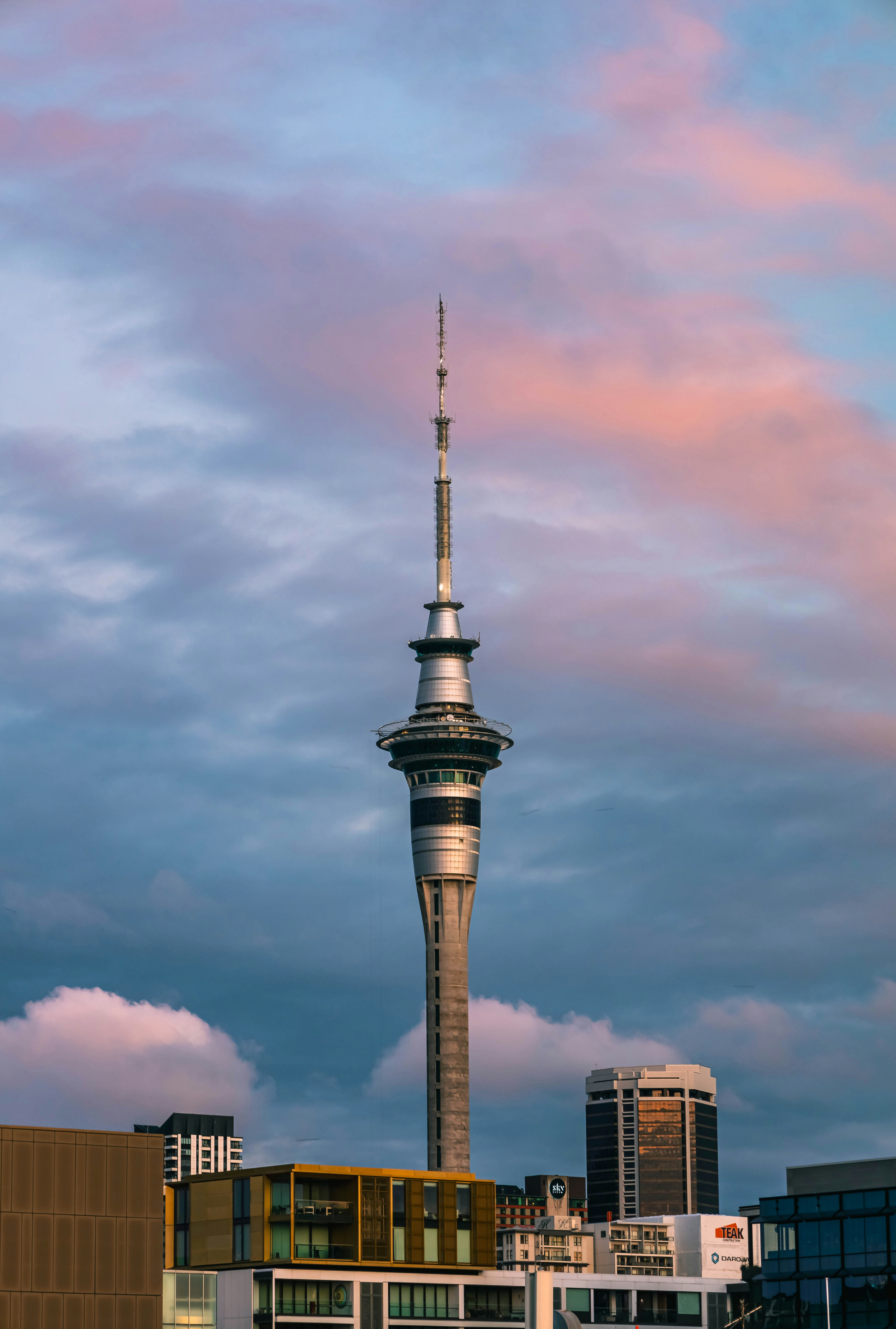 Sky Tower rising above urban buildings under a pastel sky at dusk.
