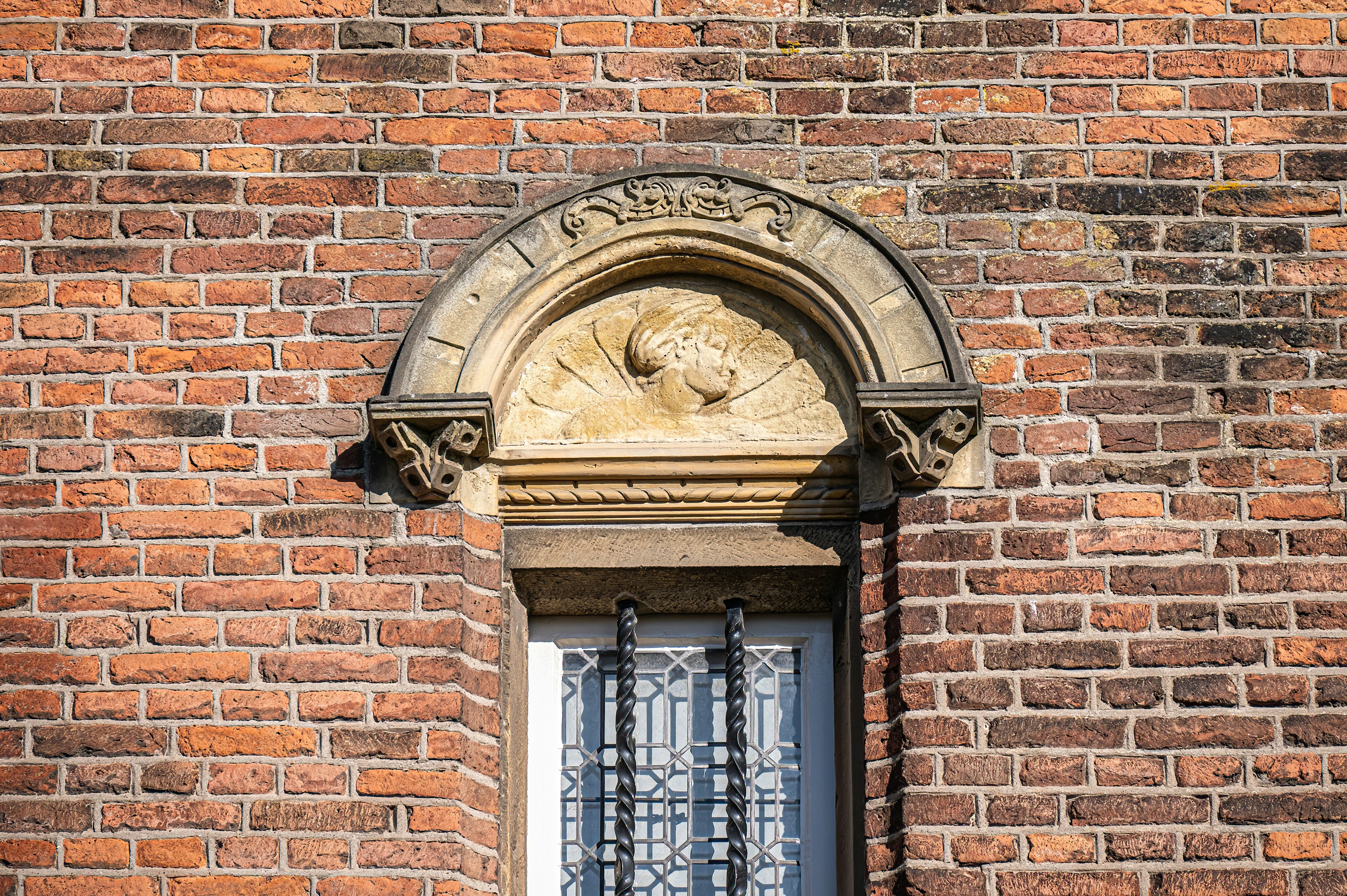 Arched Stone Ornament Above a Brick-Walled Window