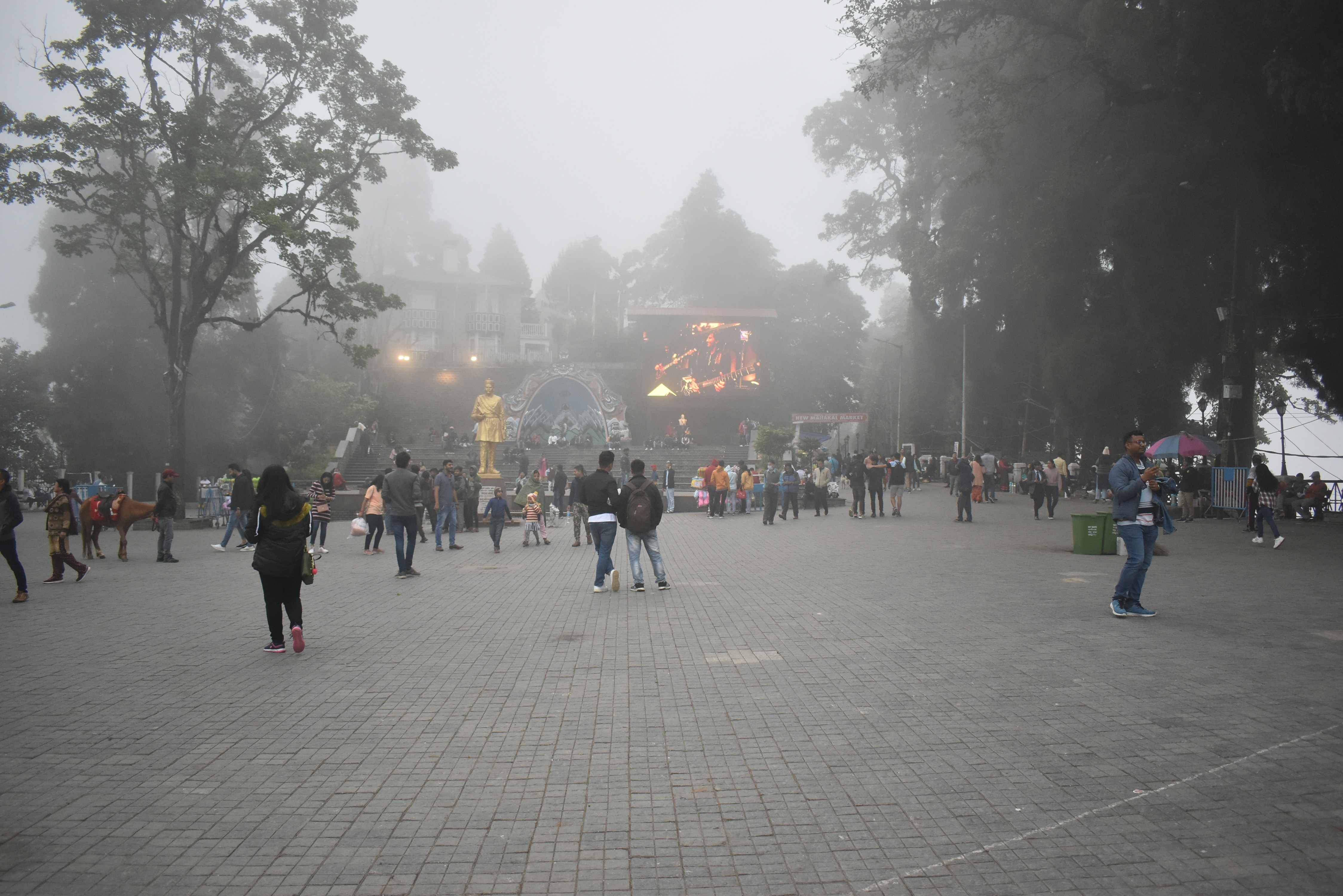 Fog-Laced Plaza: Stage Lights Pierce the Evening Haze