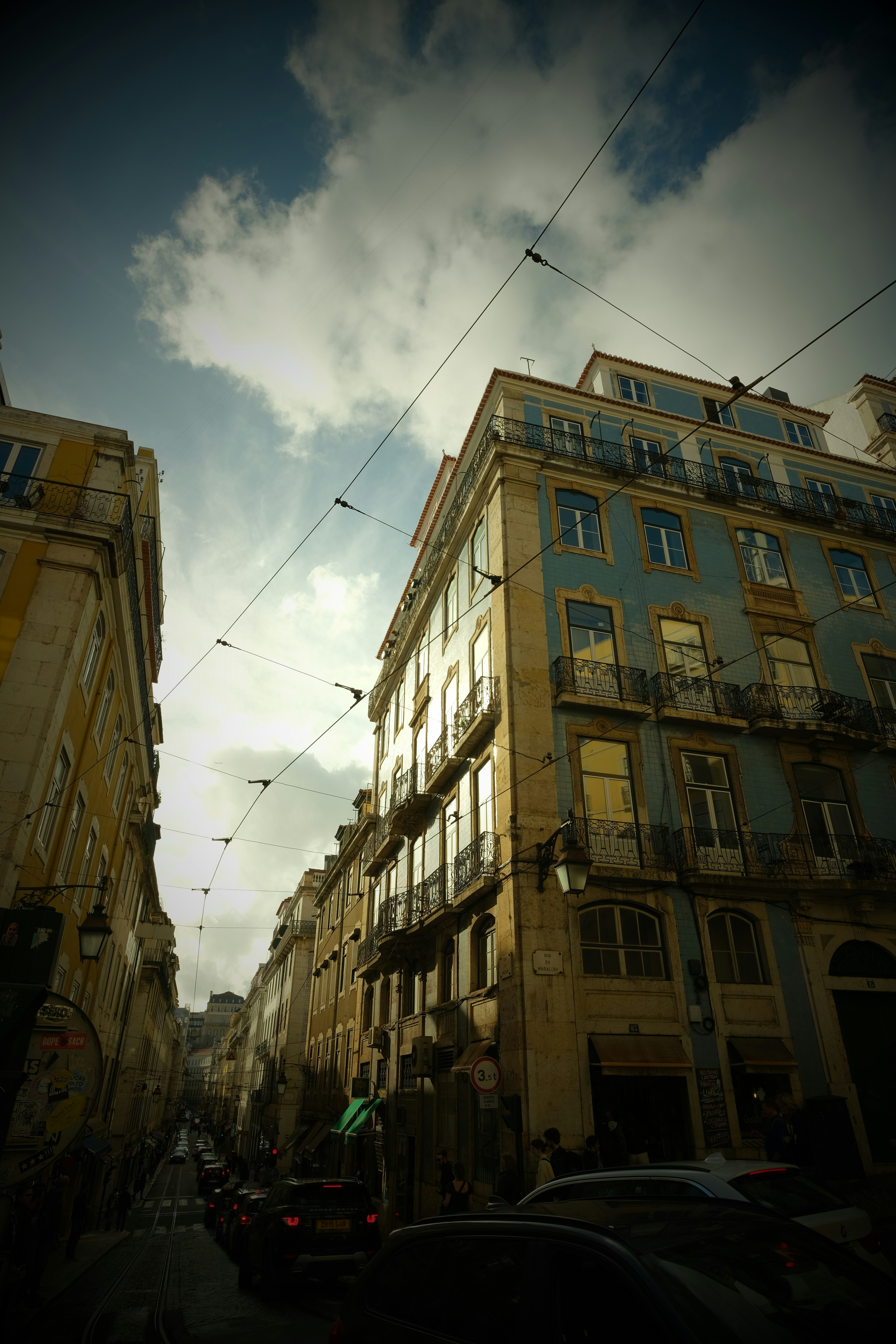 Blue Facades Under a Sky of Wires: A Narrow Street Portrait