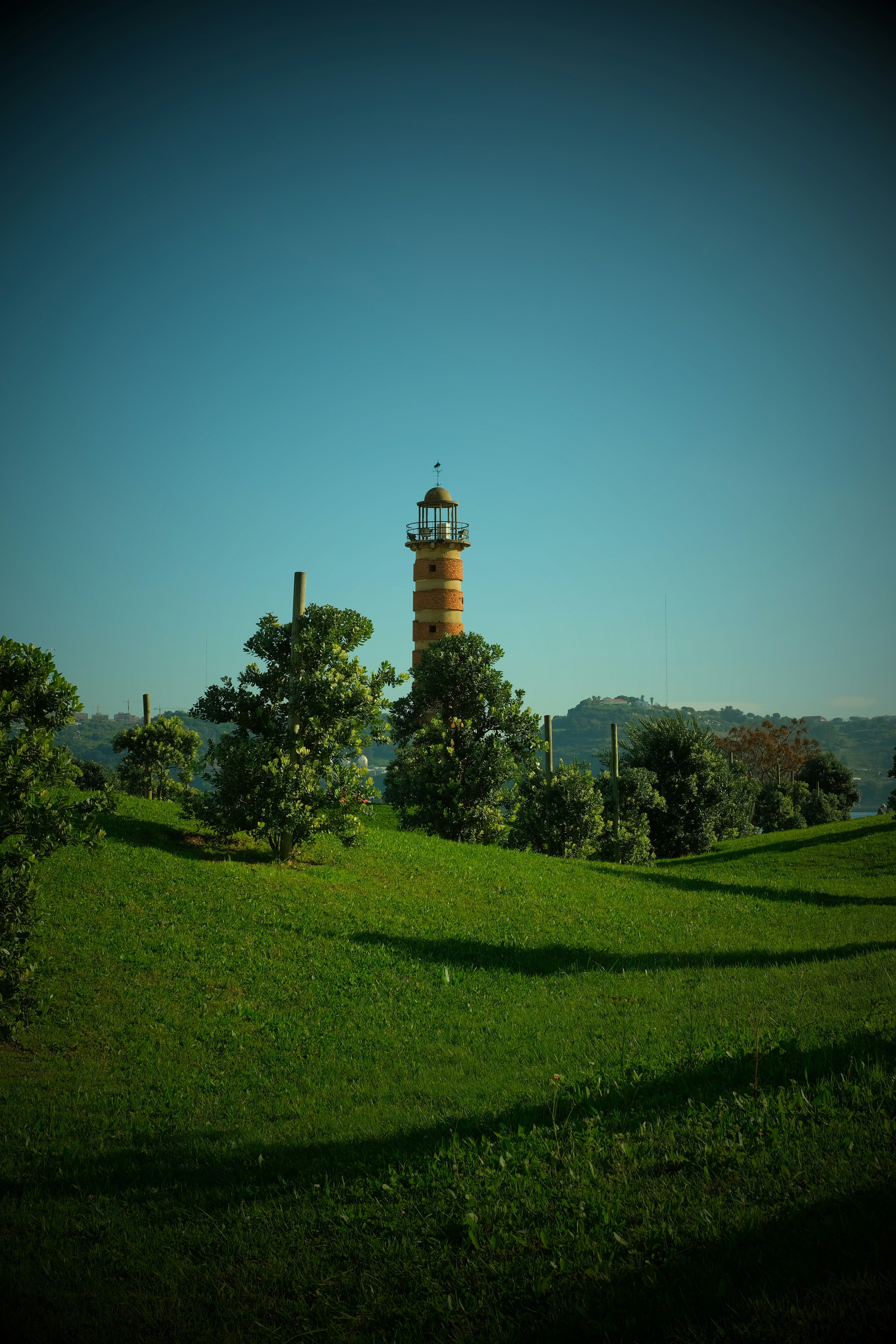 Red-Striped Beacon on a Verdant Hill: A Quiet Landscape Under Blue Skies